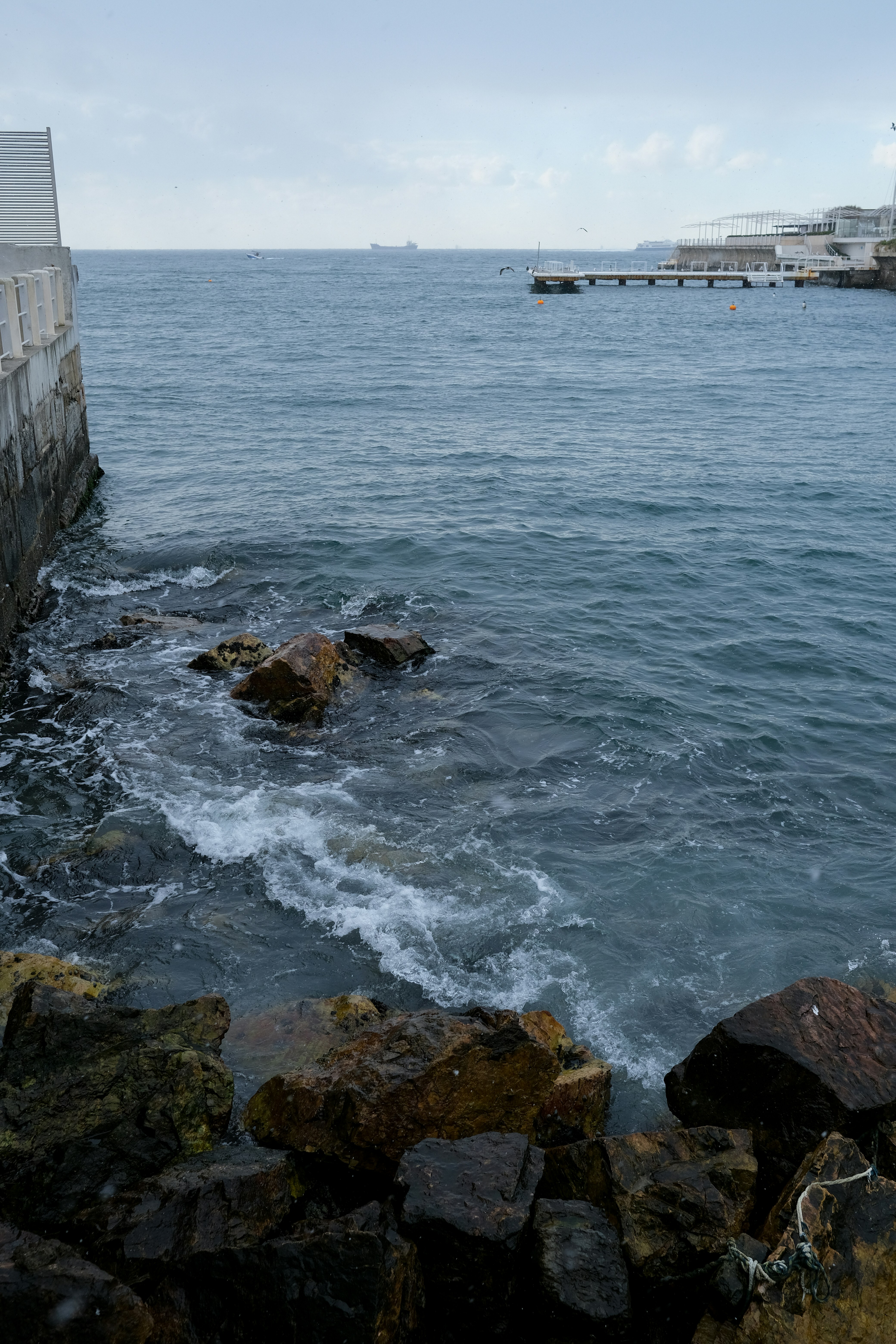 Coastal Breakwater: Blue Sea Meets Rugged Rocks Under a Calm Sky