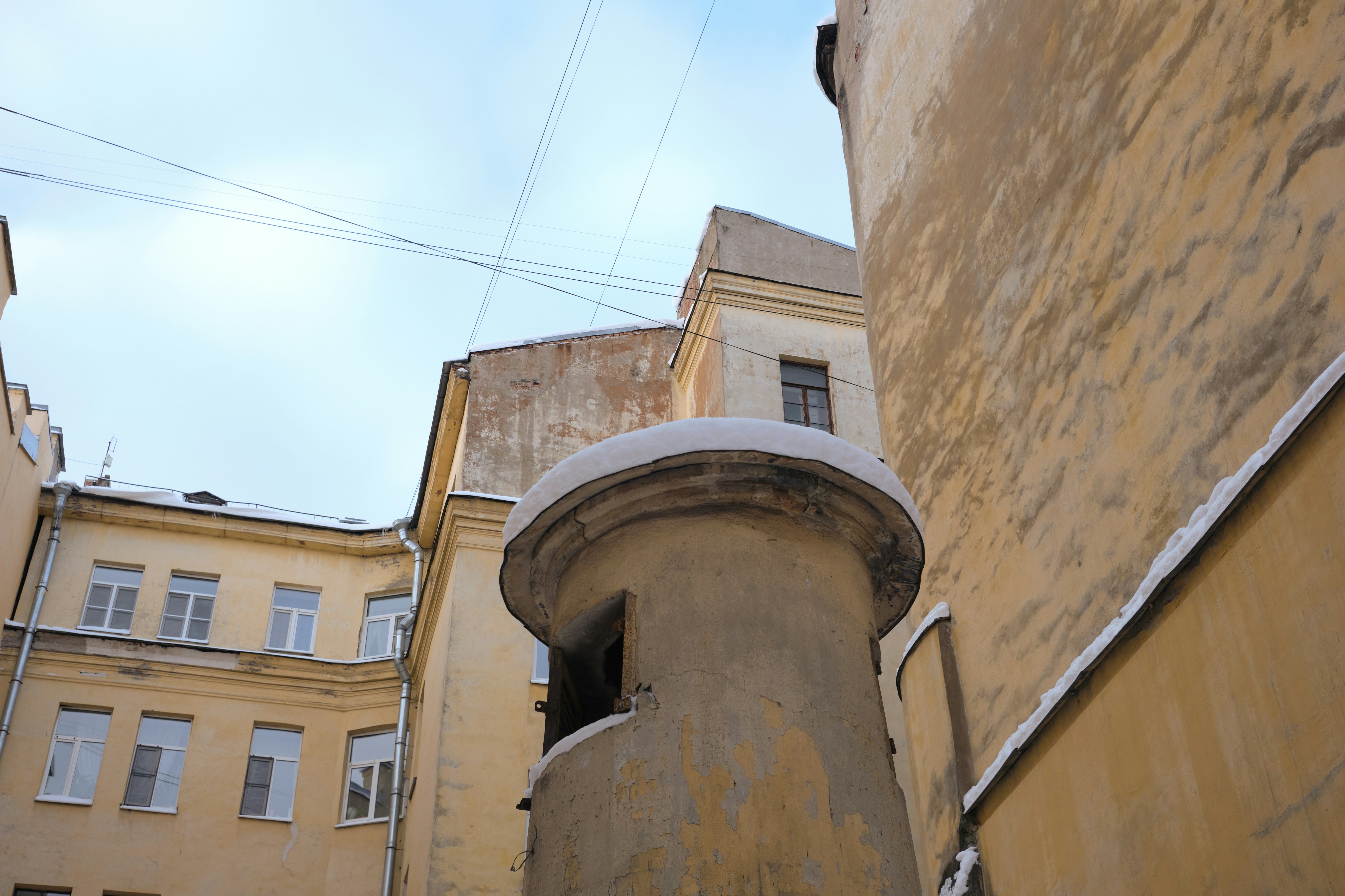 Cylindrical turret against sunlit yellow walls in an urban courtyard