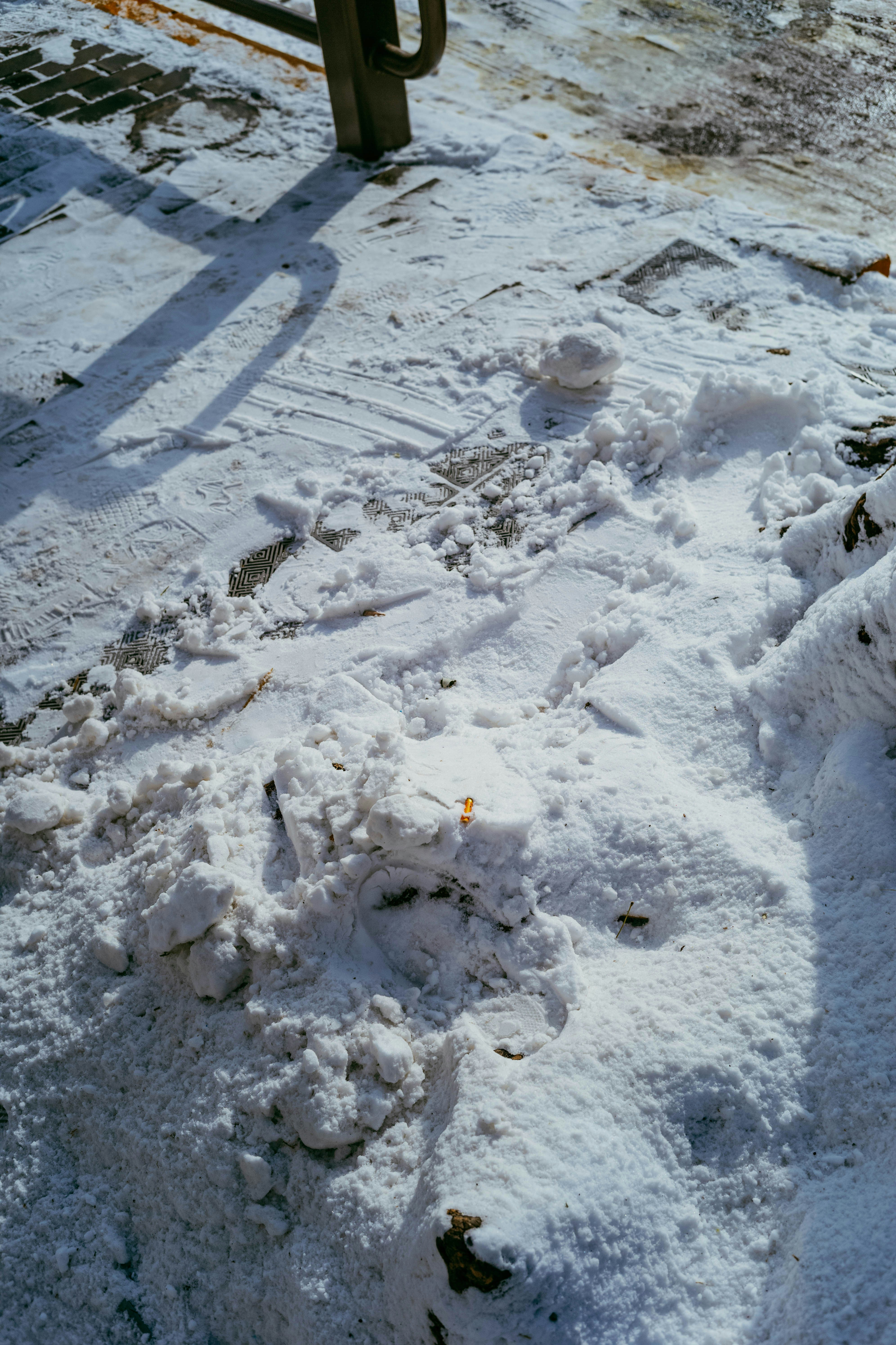 Snowy Pathway Imprint: Trampled Snow and Footmarks Near a Metal Handrail