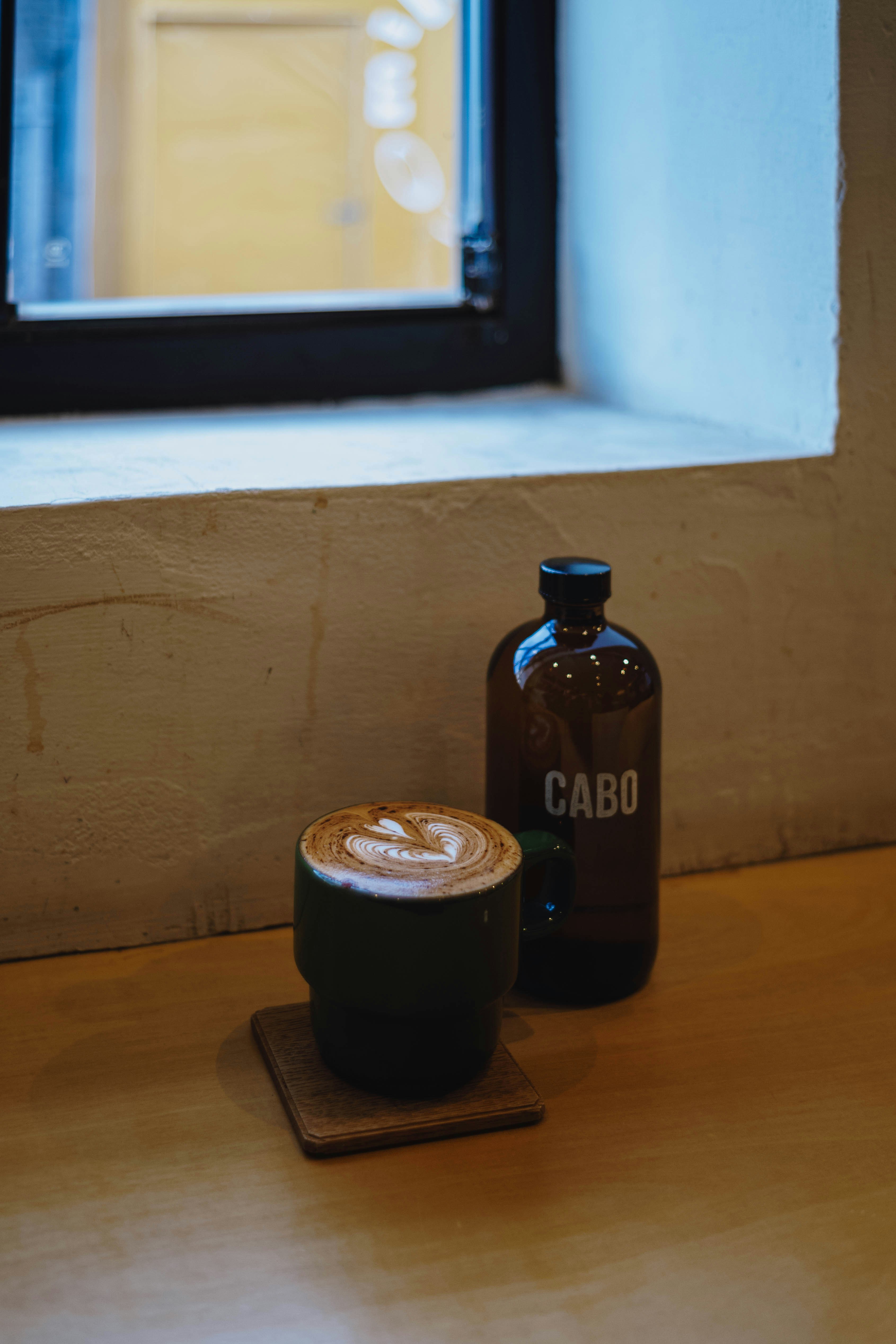 Coffee Studio Still Life: Latte Art and a CABO Bottle by the Window