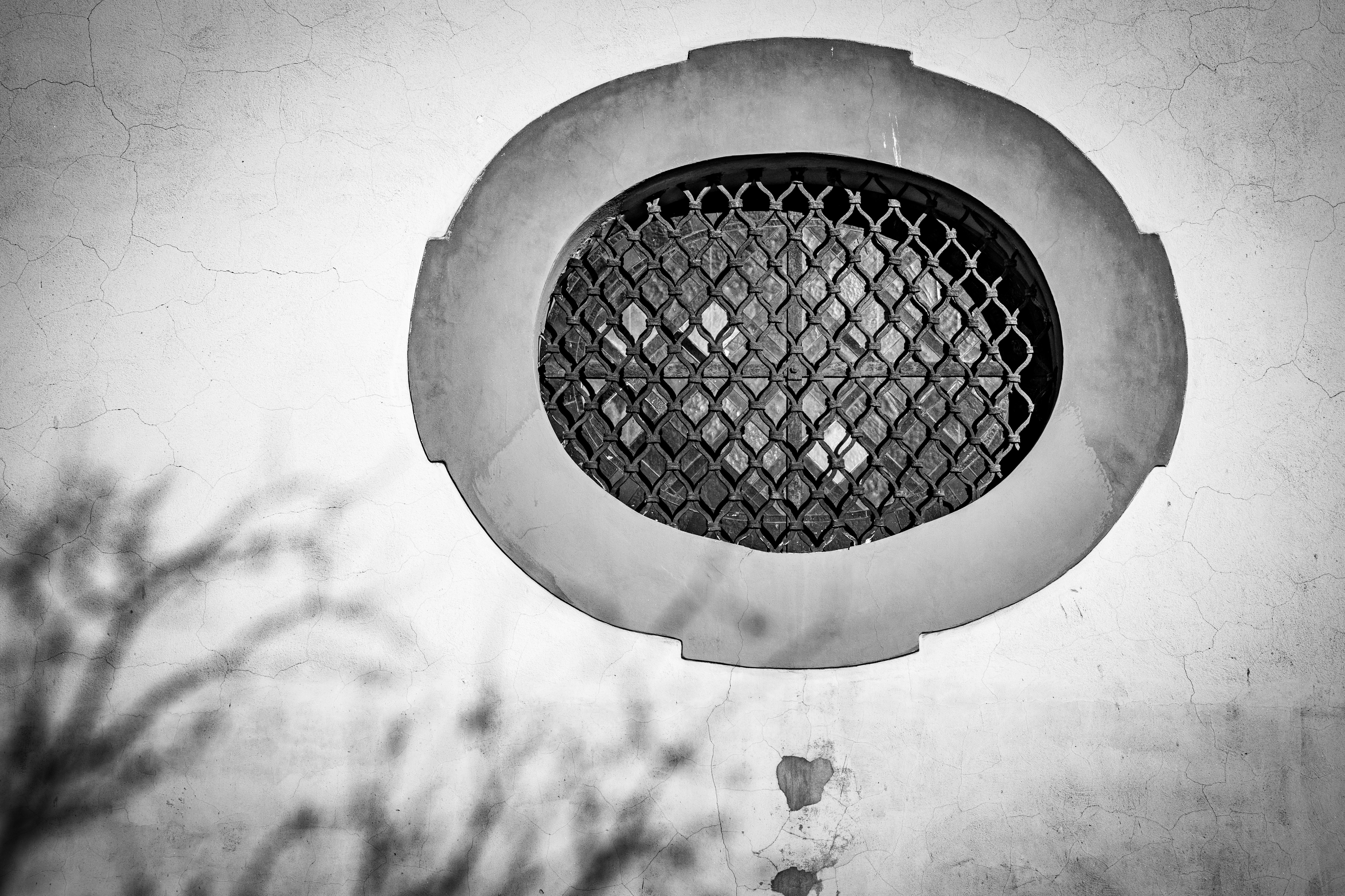 Circular vent with lattice guard on a sunlit wall