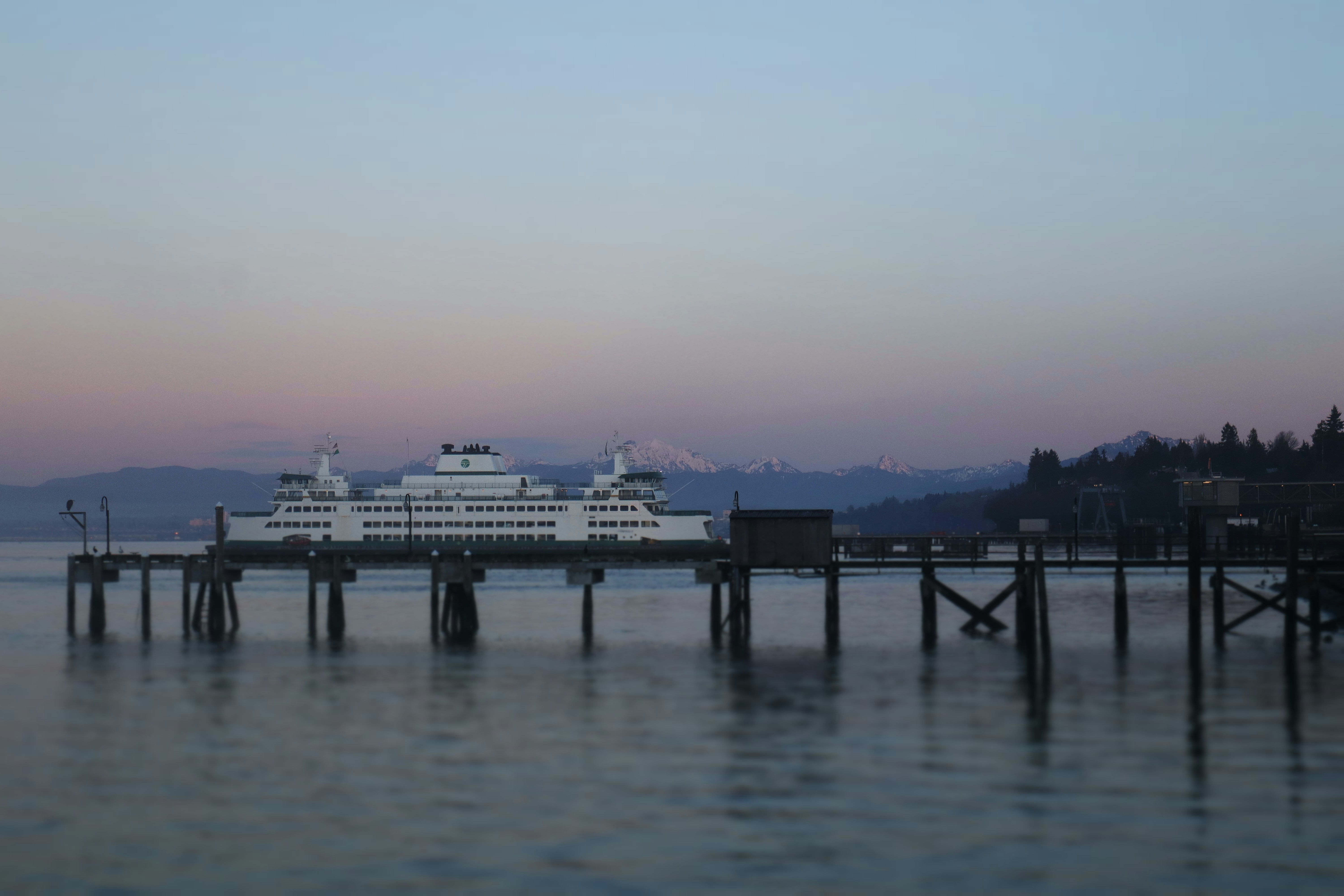Calm Harbor at Dusk: Ferry Pier Silhouettes Against Snow-capped Peaks