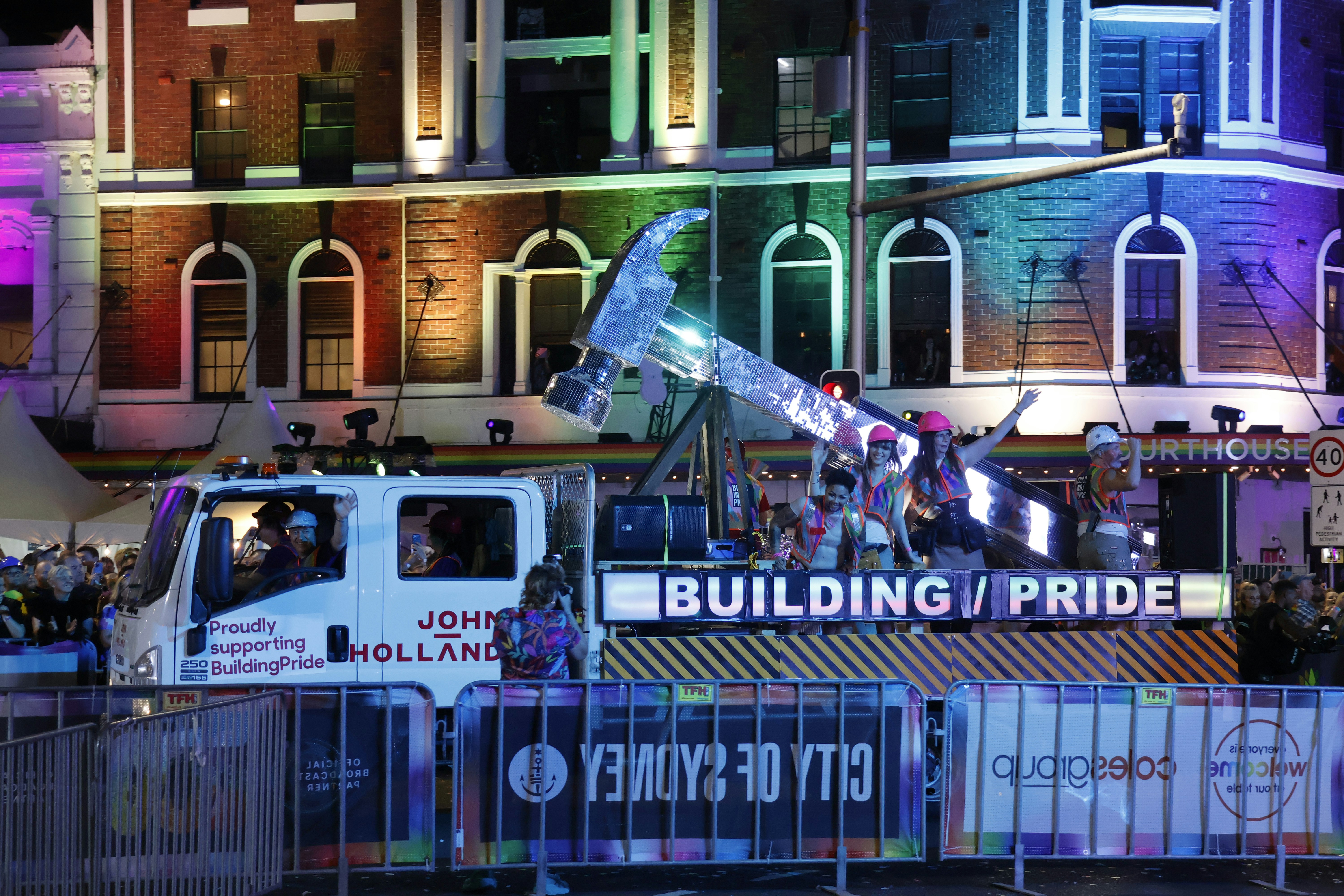 Color-Charged Parade Float Surging Past a Historic Brick Facade