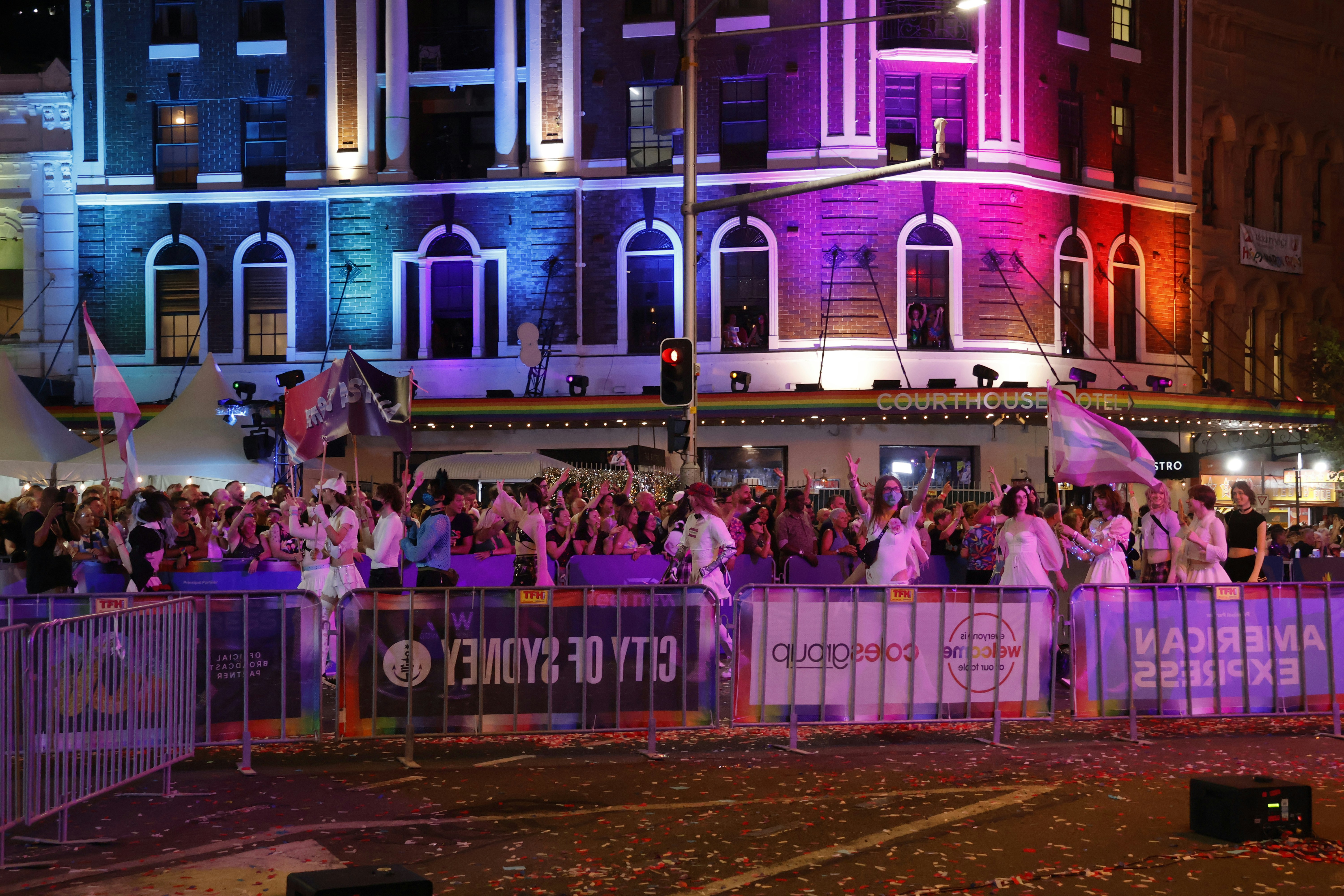 Neon-lit Street Party Behind a Rainbow-Flooded Facade