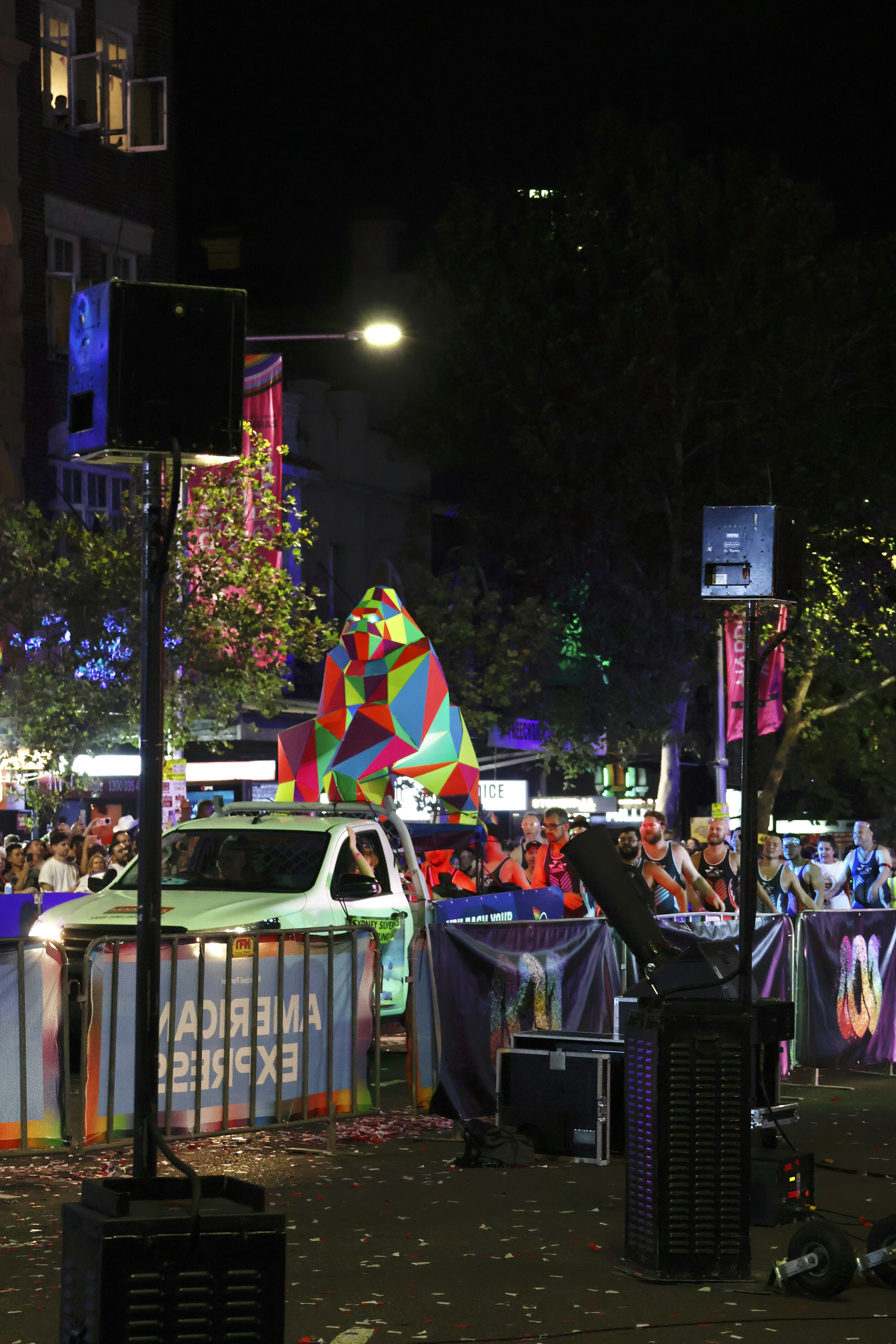 Colorful geometric sculpture anchors a lively night parade scene