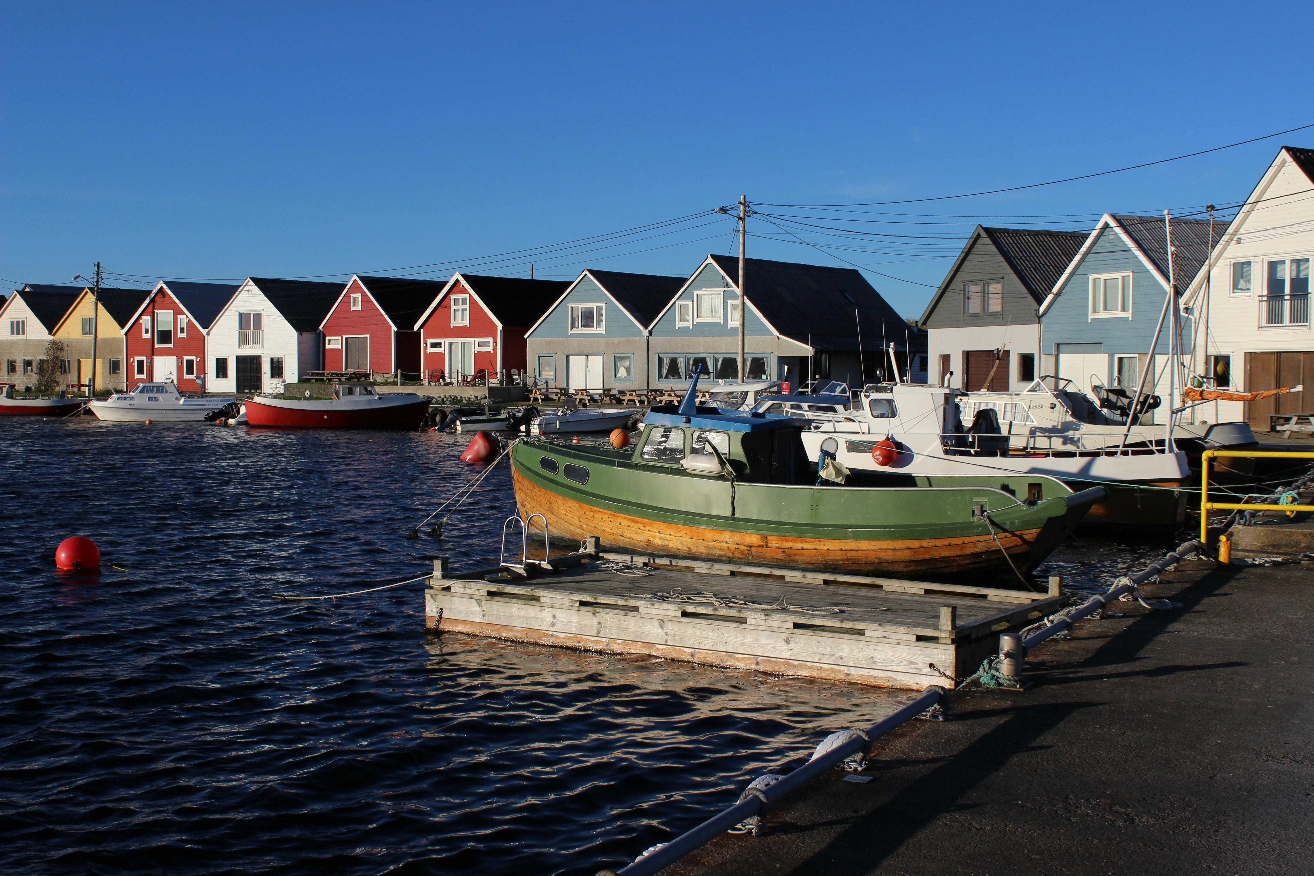 Colorful Rowboats and pastel houses lining a calm harbor