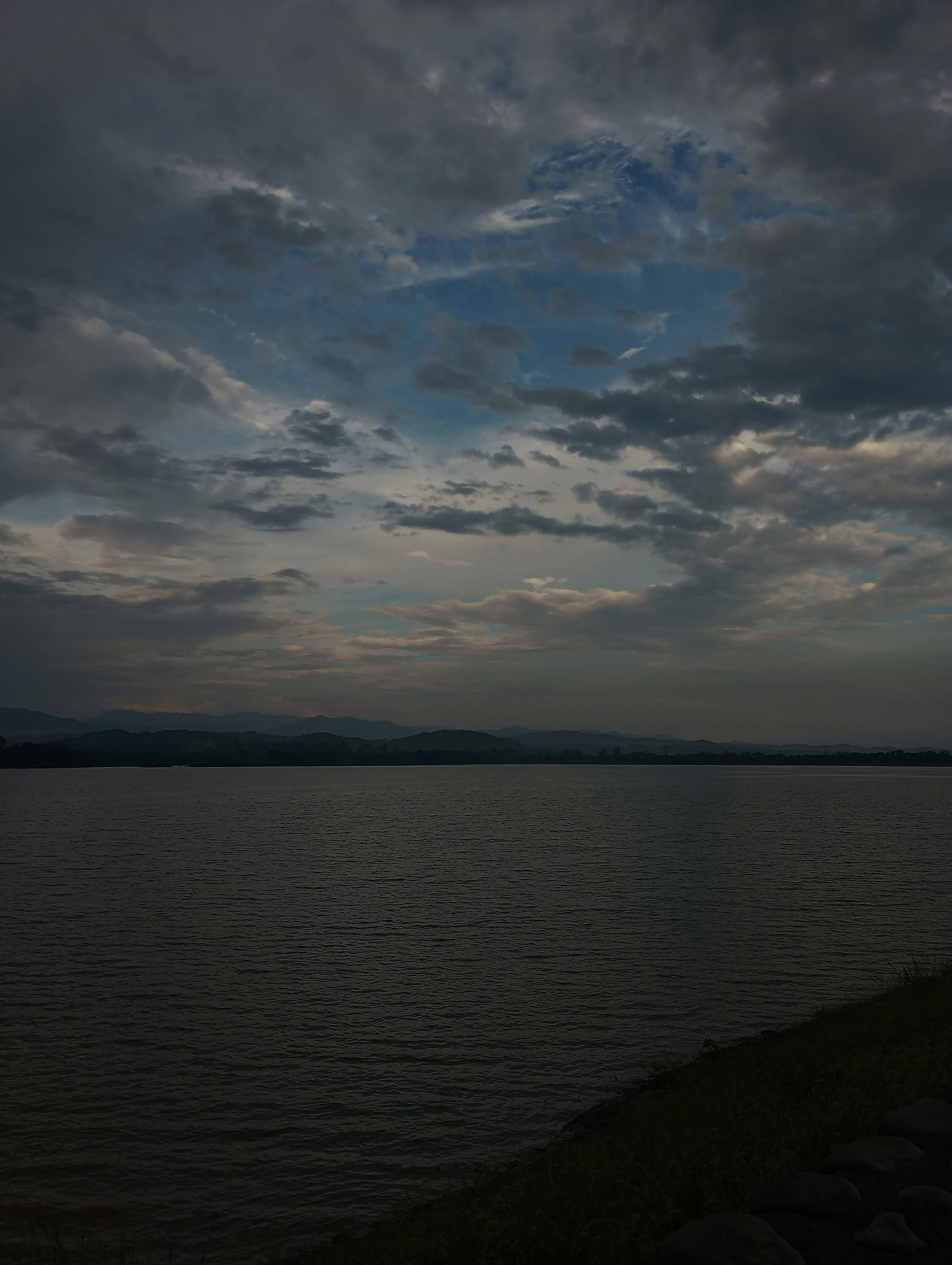 Dark clouds over a calm lake at dusk.
