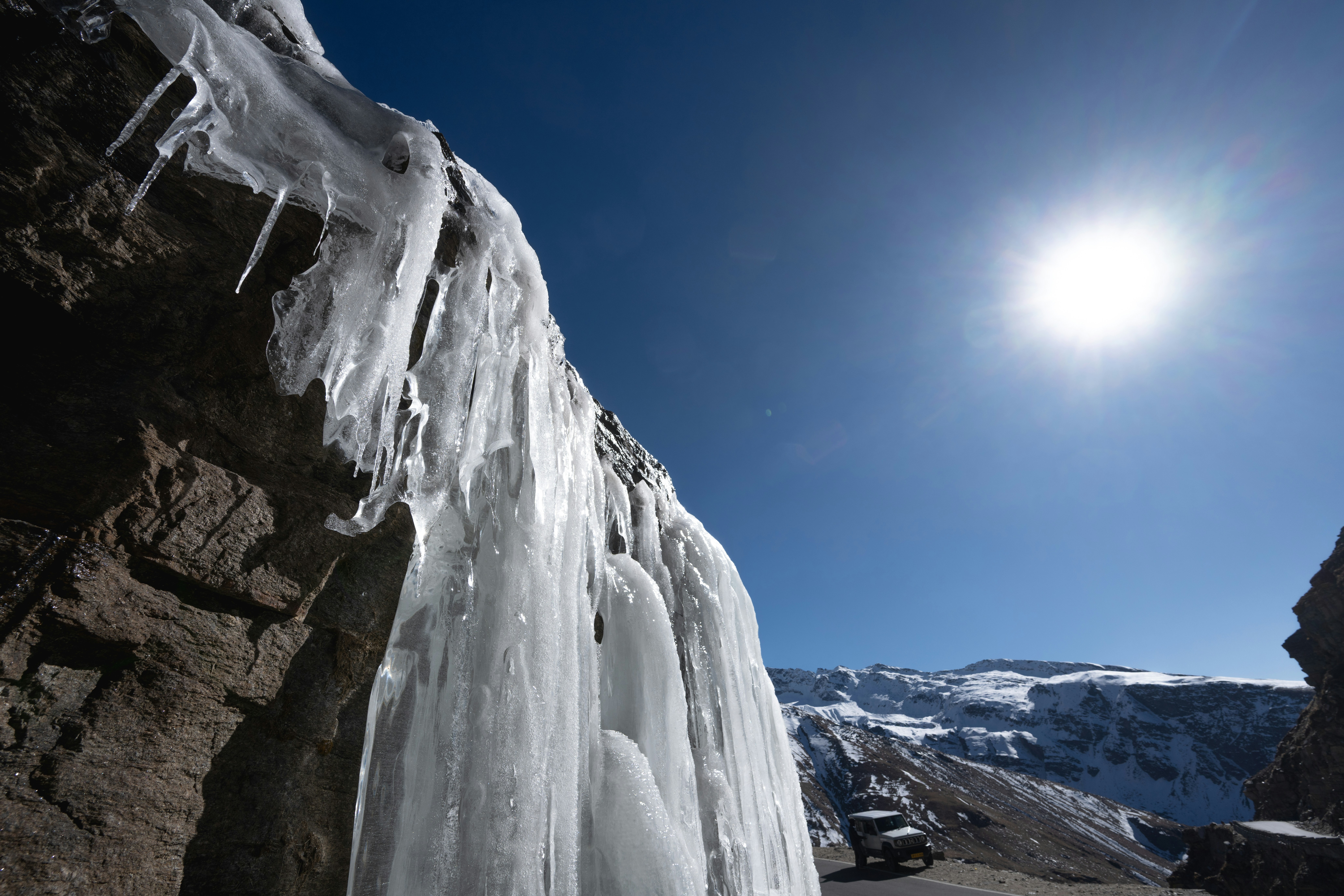 Frozen Cascade: Icicles Clinging to Mountain Edge Under Alpine Sun