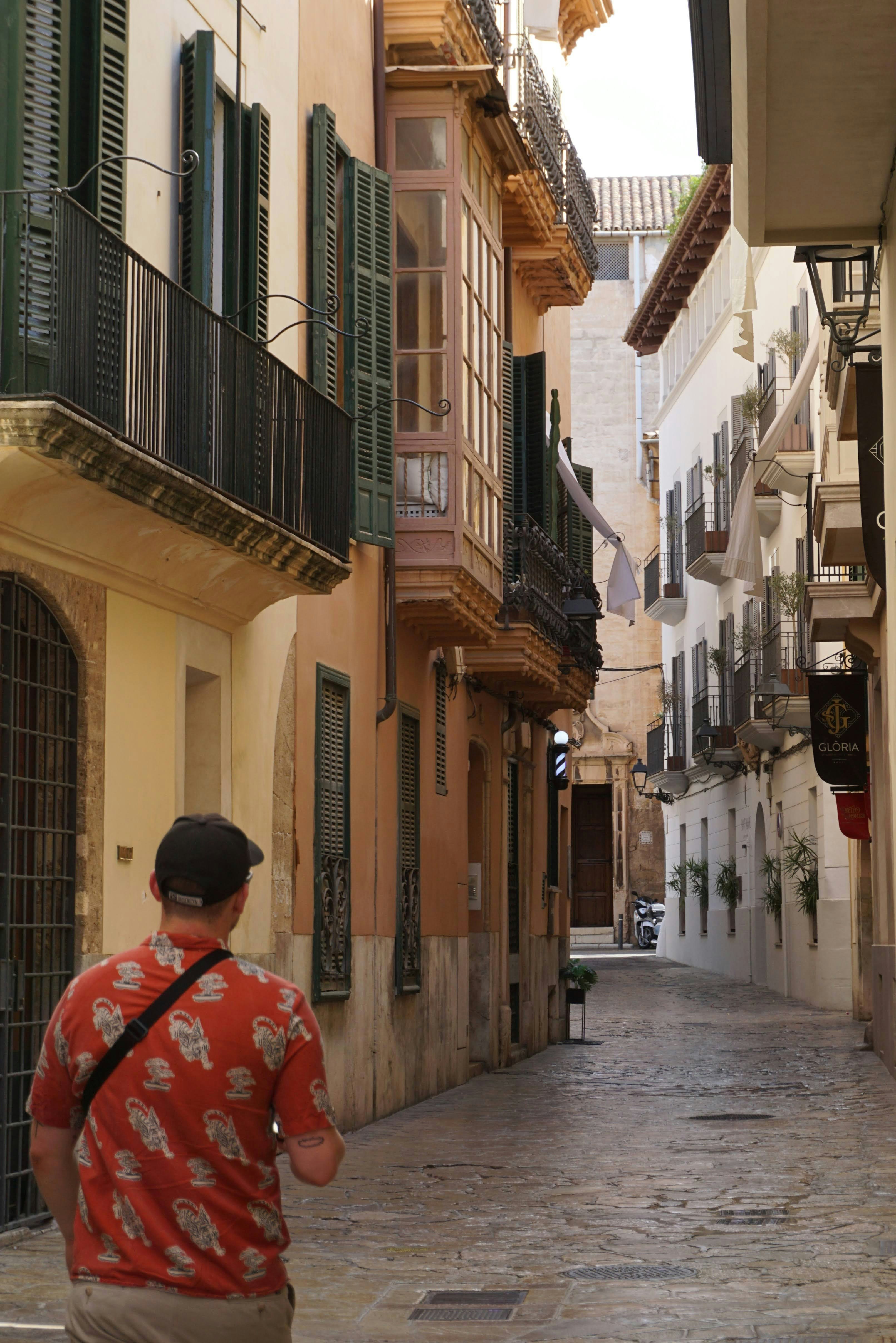 Warm Tuscan Alley Stroll: A Traveler in a Red Shirt Descends a Sunlit Calle