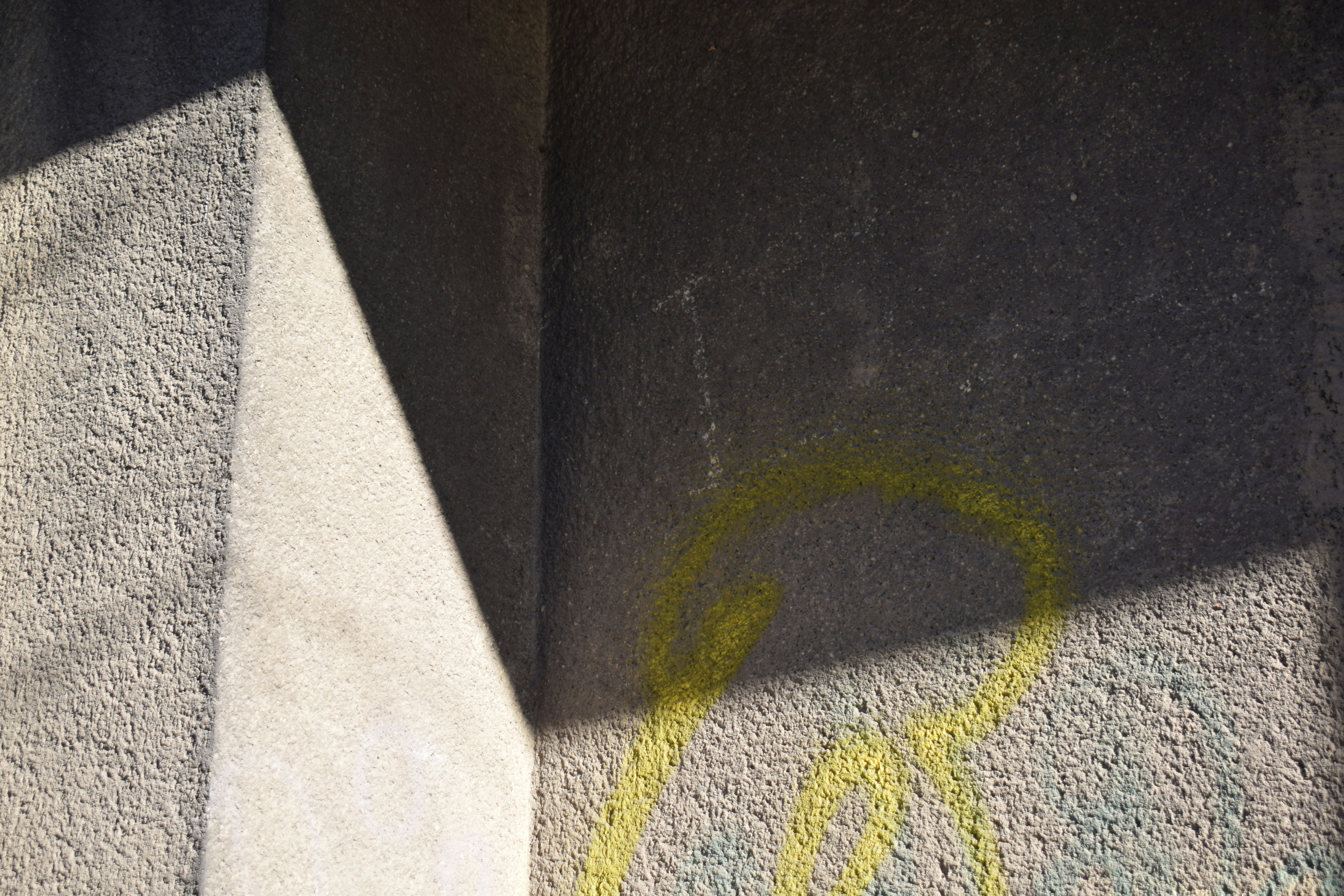 Graffiti Glyph on Sunlit Concrete Wall