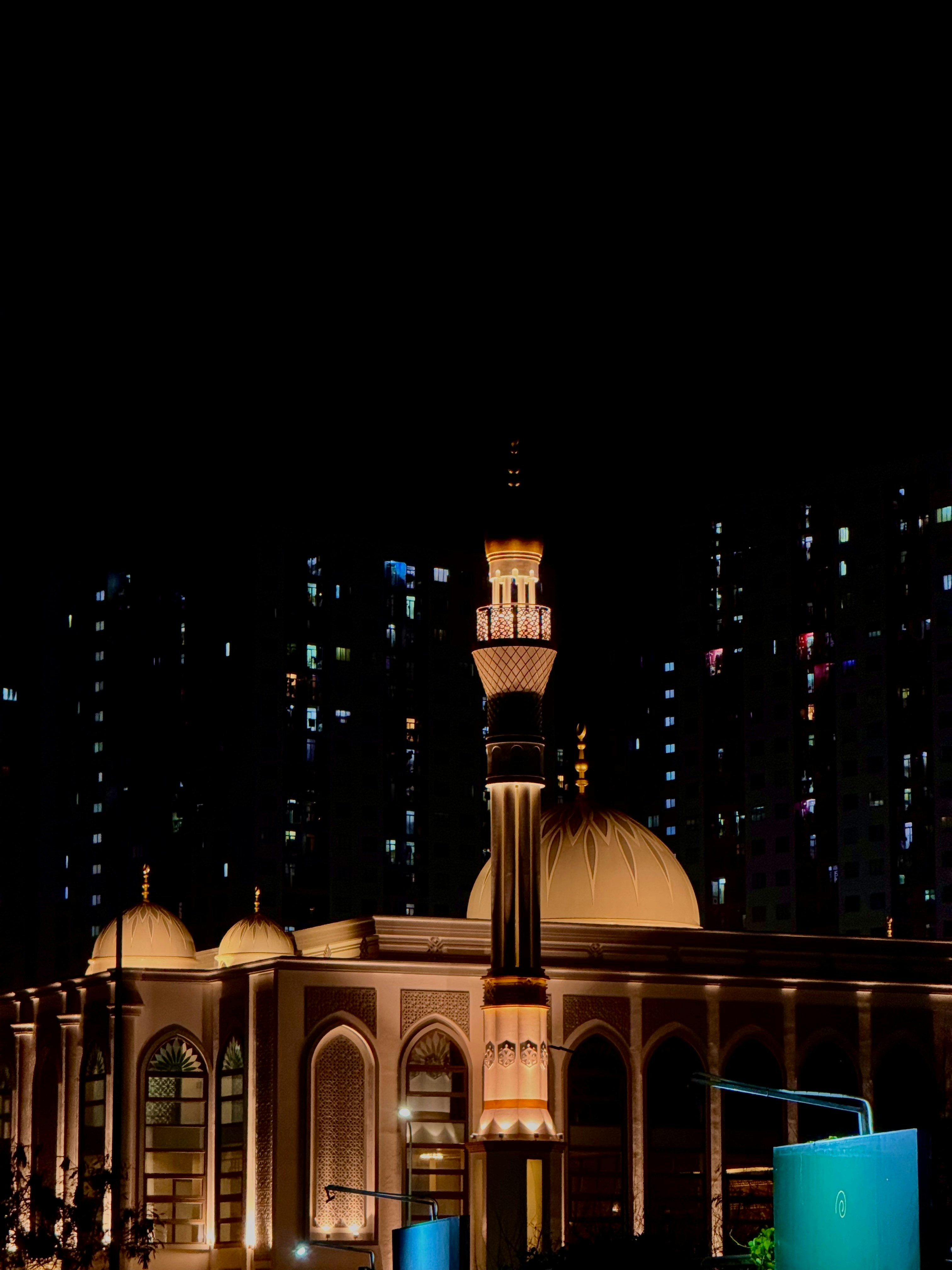 Night Mosque Spire: Illumination Amid Modern Skyline