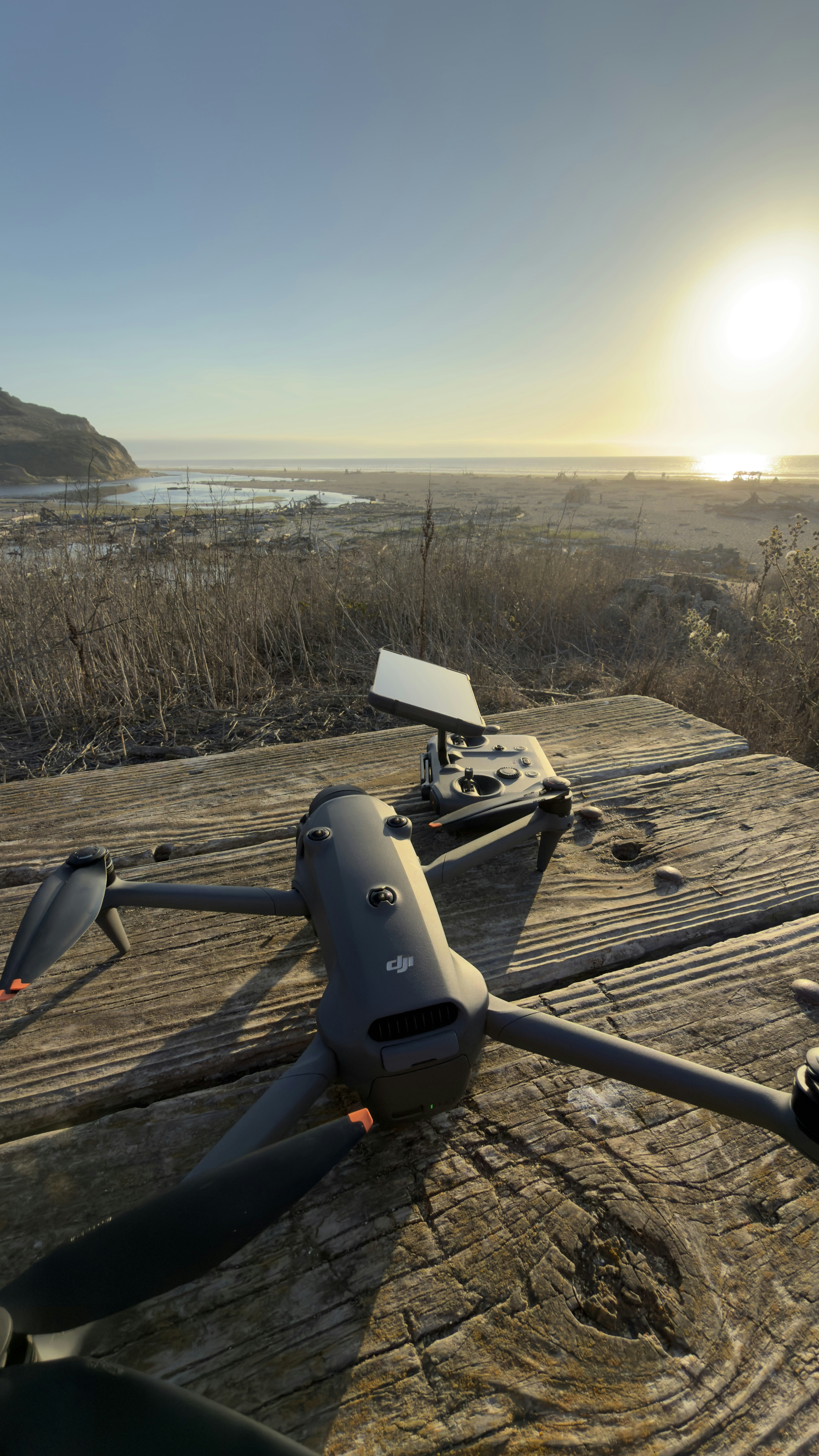 Drone Resting on Weathered Rail: Sunset Over Coastal Meadow