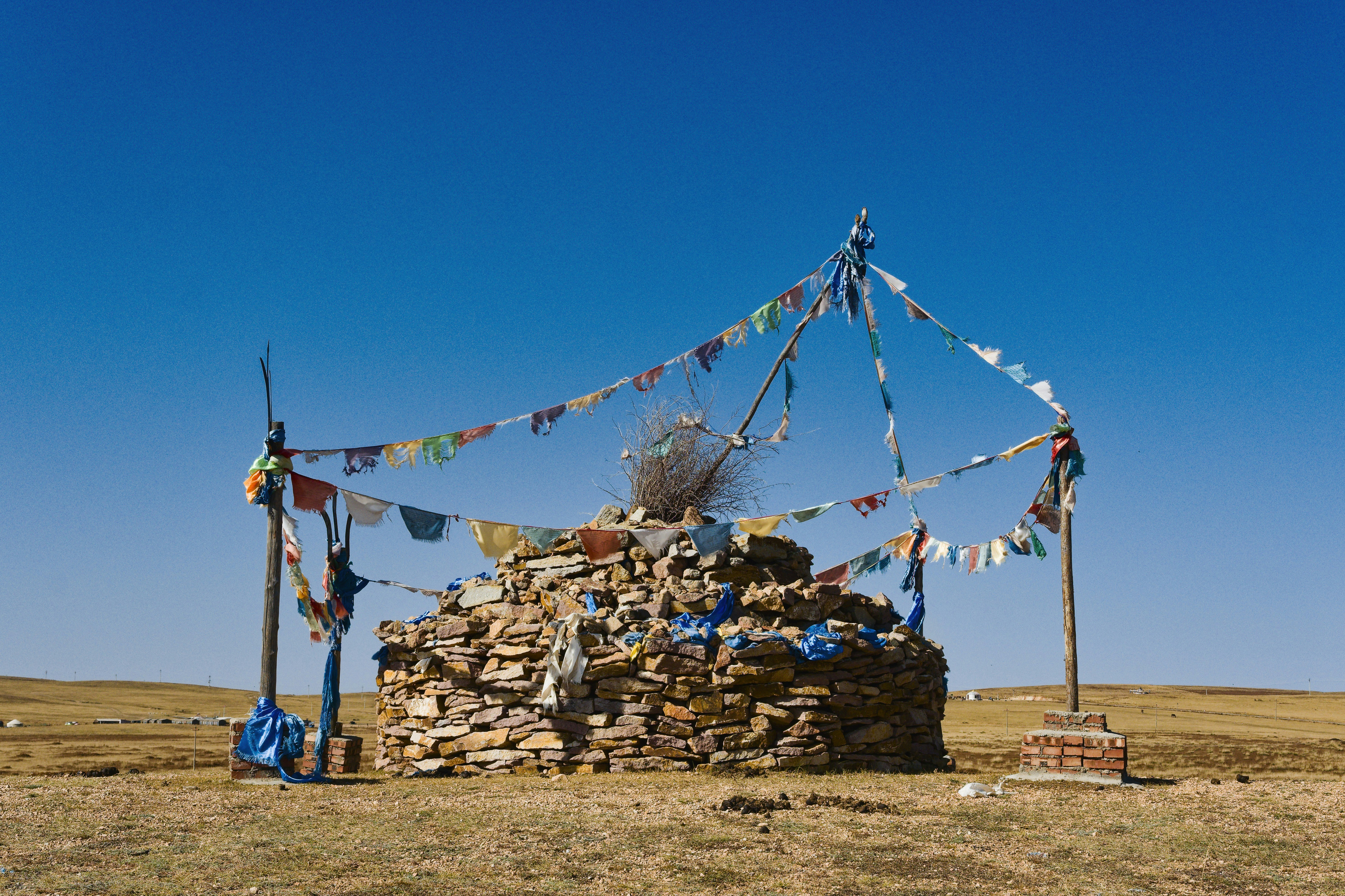 Prayer Flags Over a Lone Stone Structure in a Vast Grassland