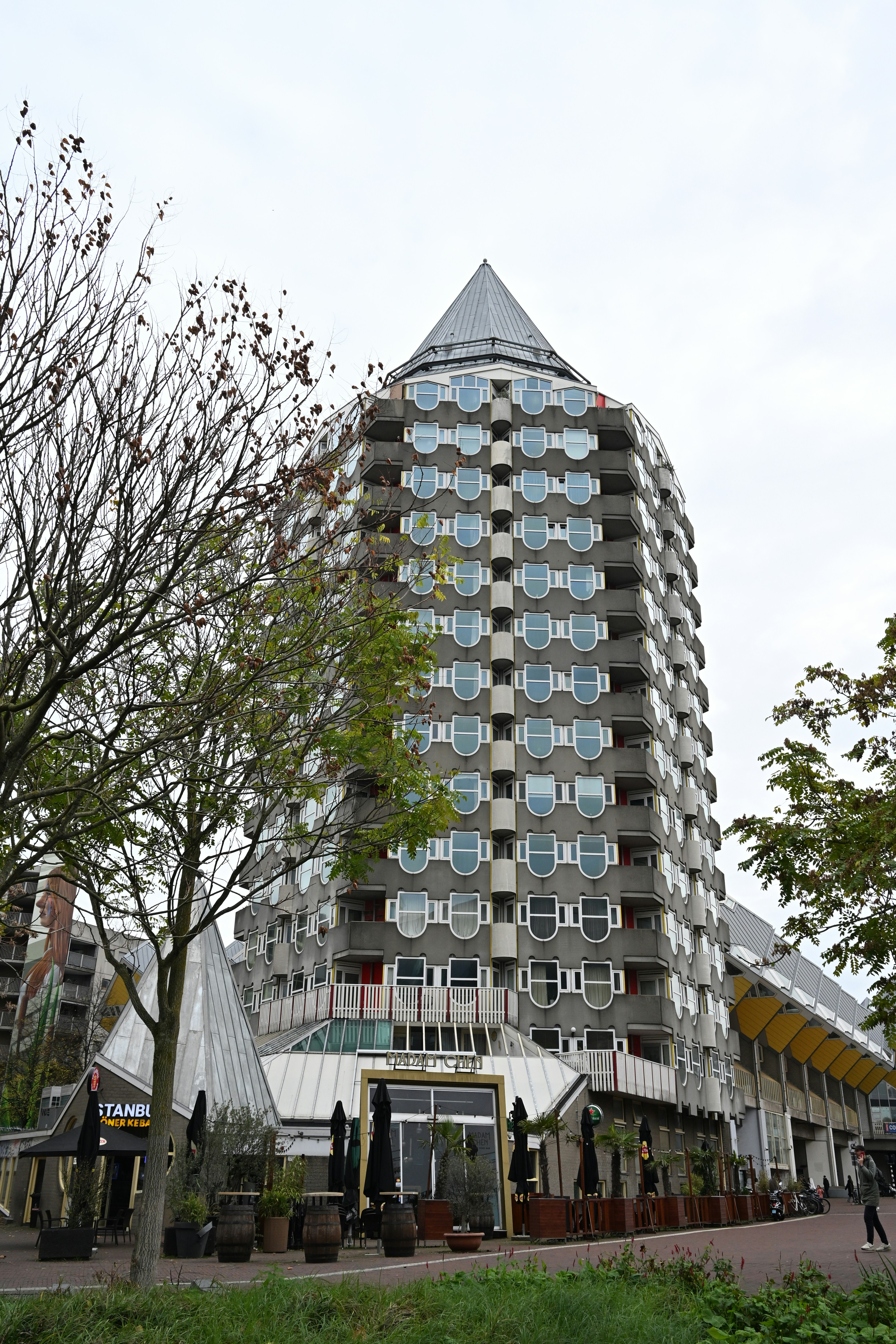 Towering Facade of a Curved-Edge Residential Structure Framed by Street-Level Activity