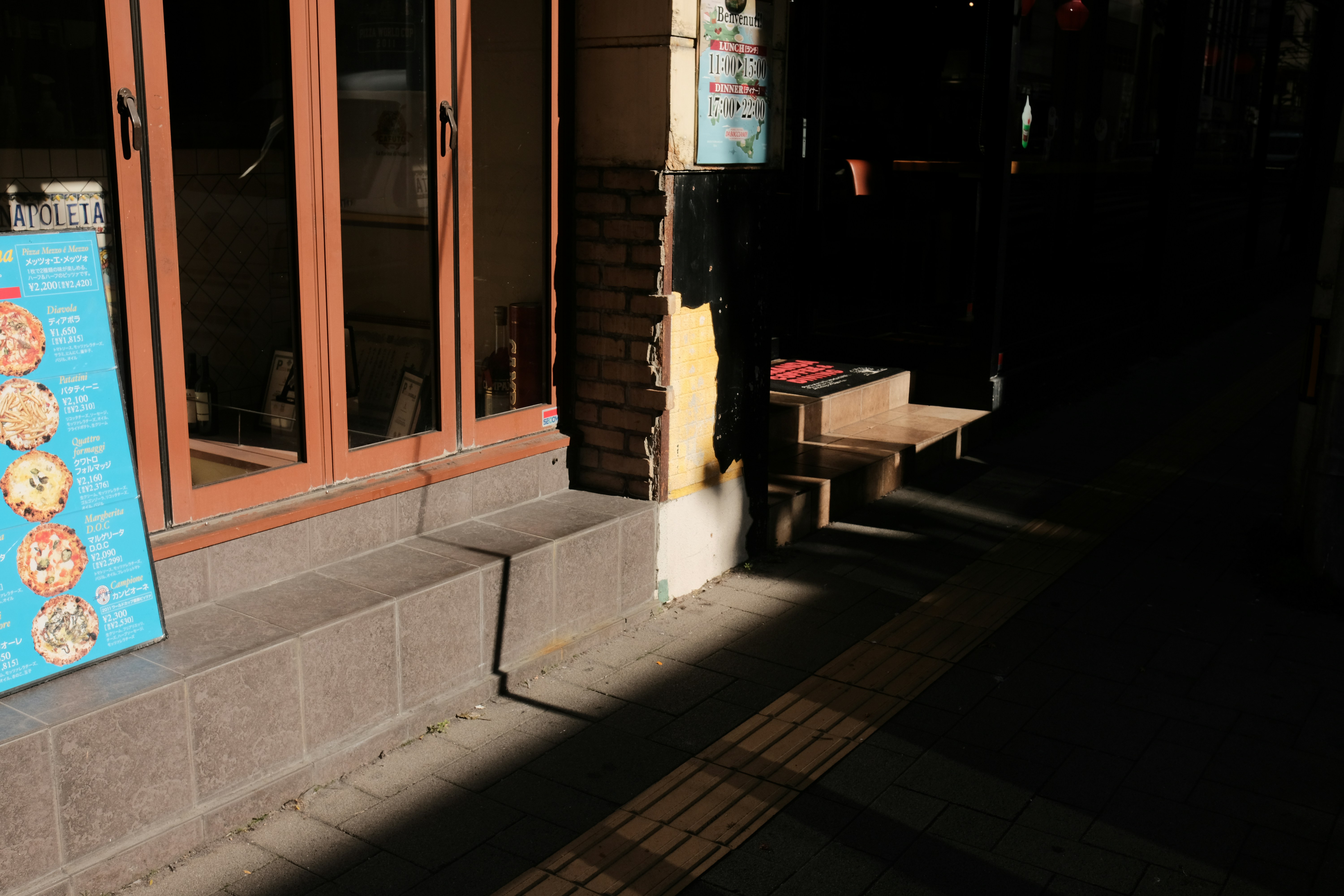 Sunlit Threshold: A Quiet Corridor of Light by a Brick-Wrown Storefront