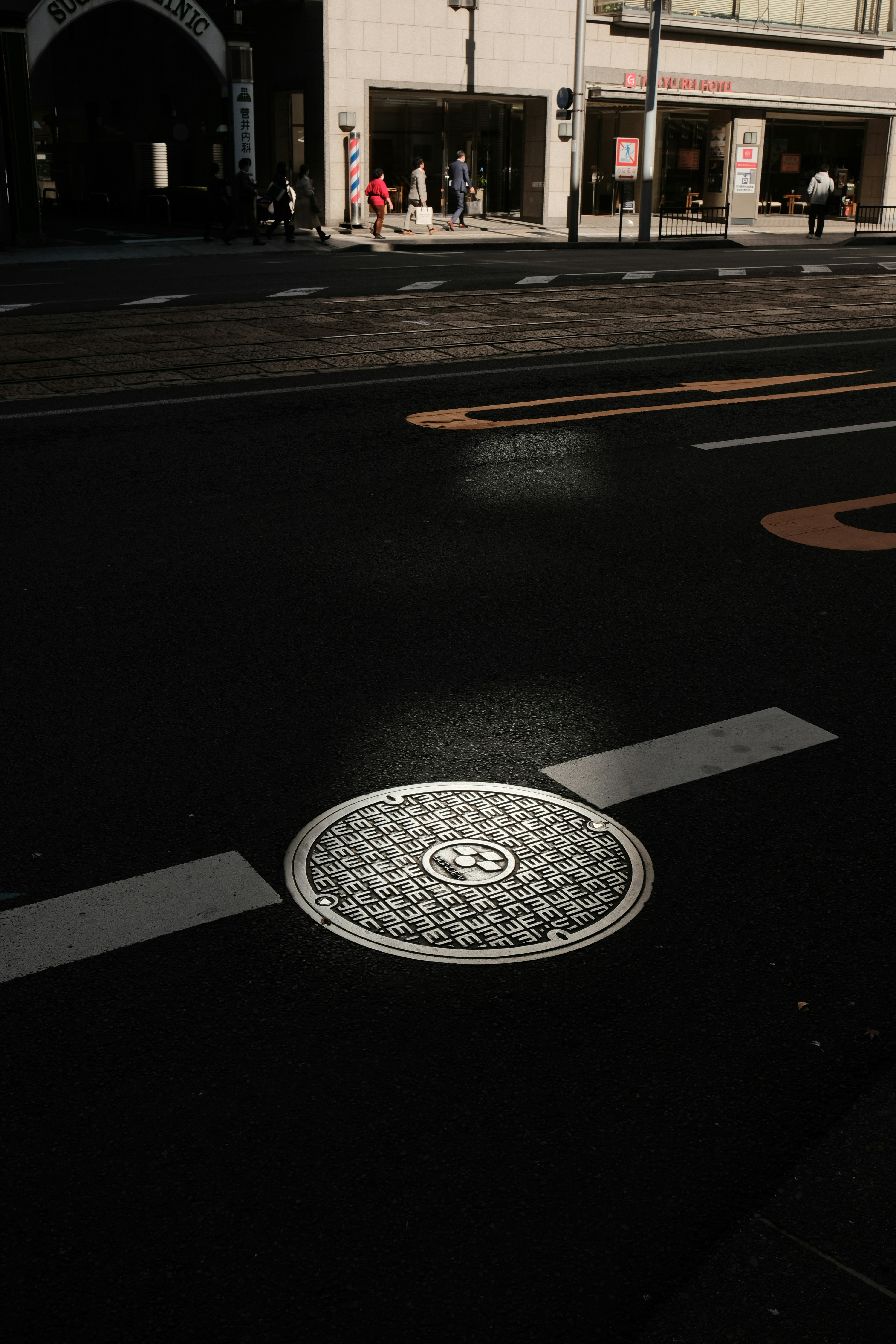 Urban Crosswalk Echoes: Manhole, Shadows, and a Quiet Facade