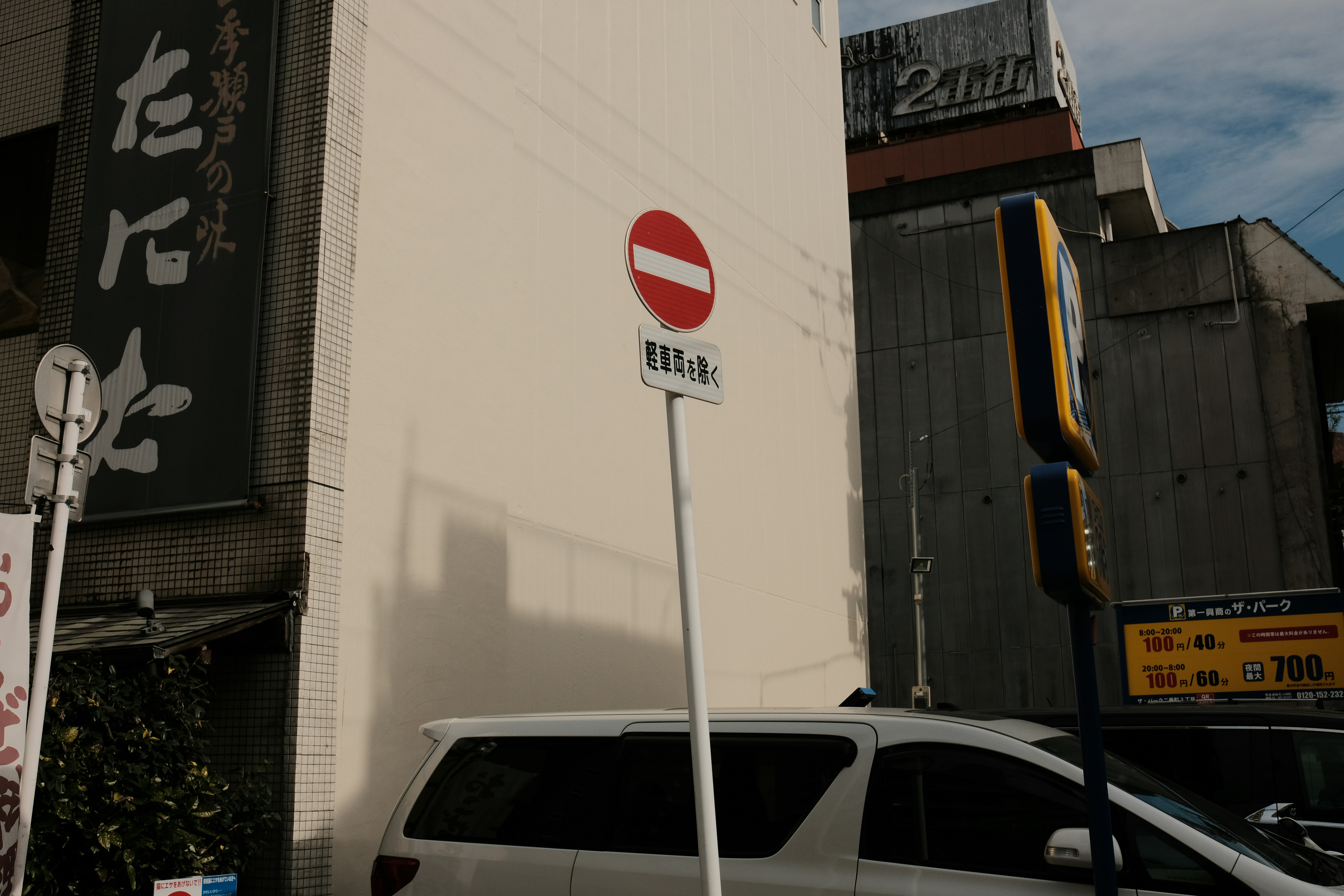 Urban Shadow Play: A No-Entry Sign Framed by Buildings and a Waiting Vehicle