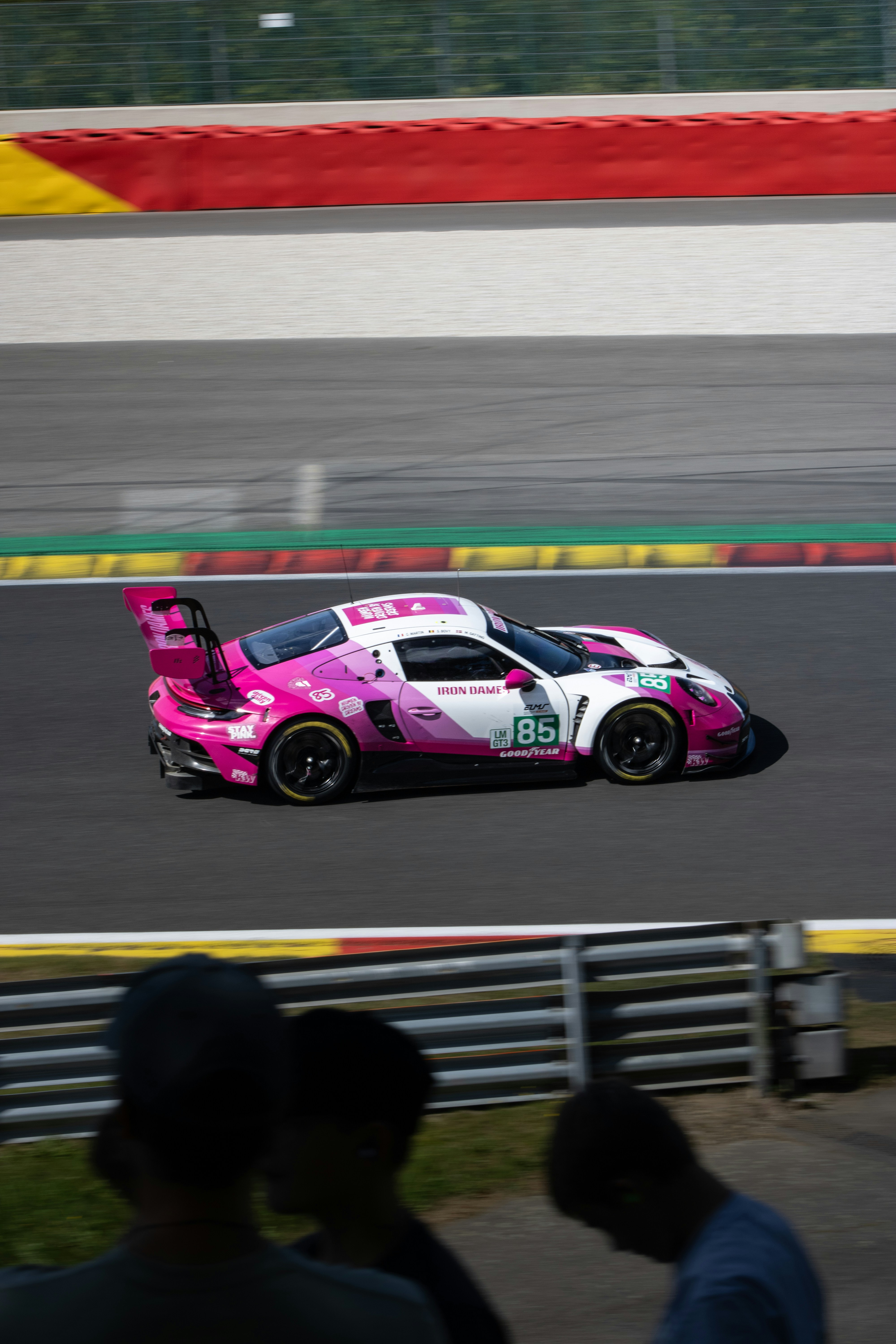 Pink racing machine powers past barriers at edge of track
