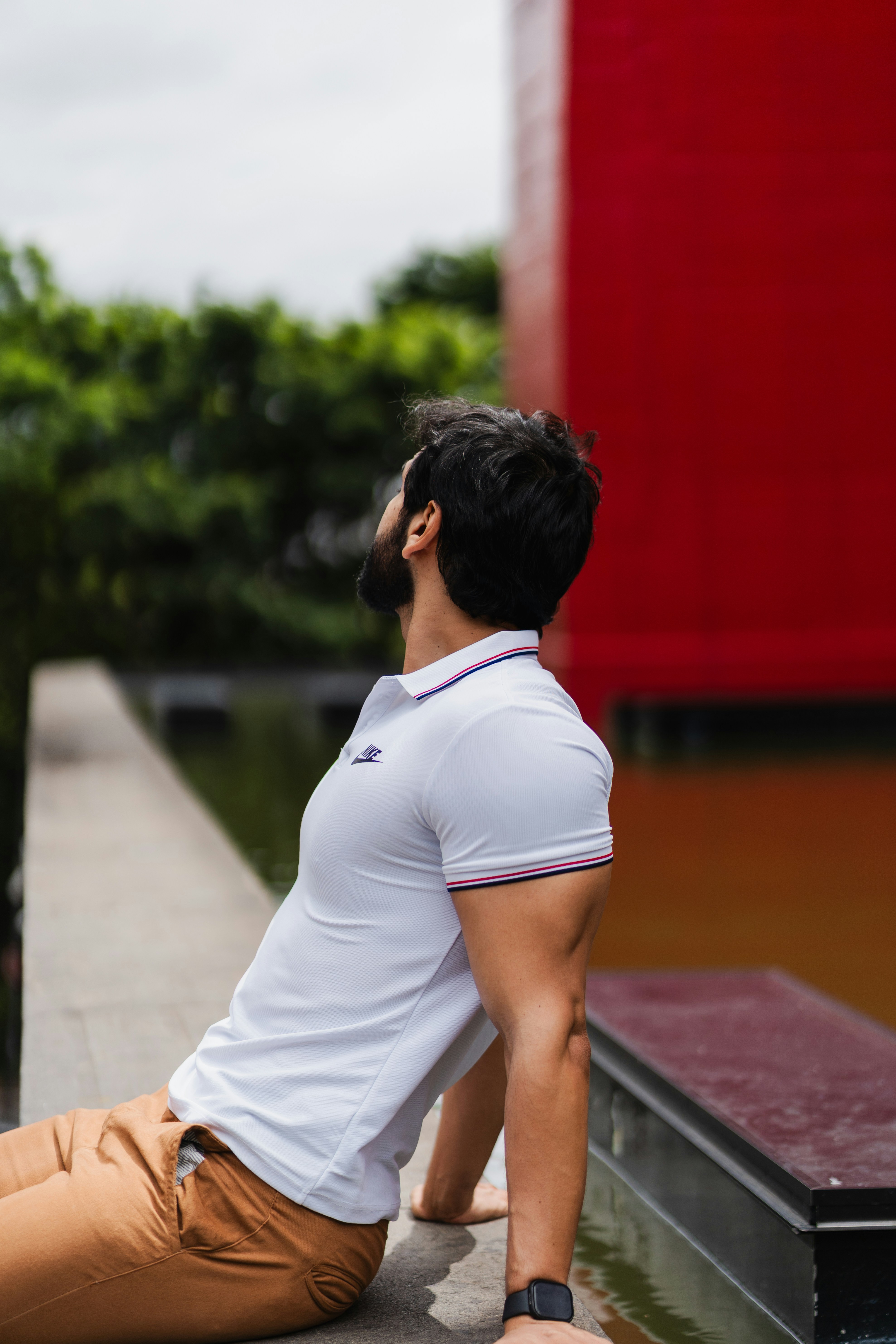 Portrait on the Pier: A Muscular Figure Against a Red Modern Marvel