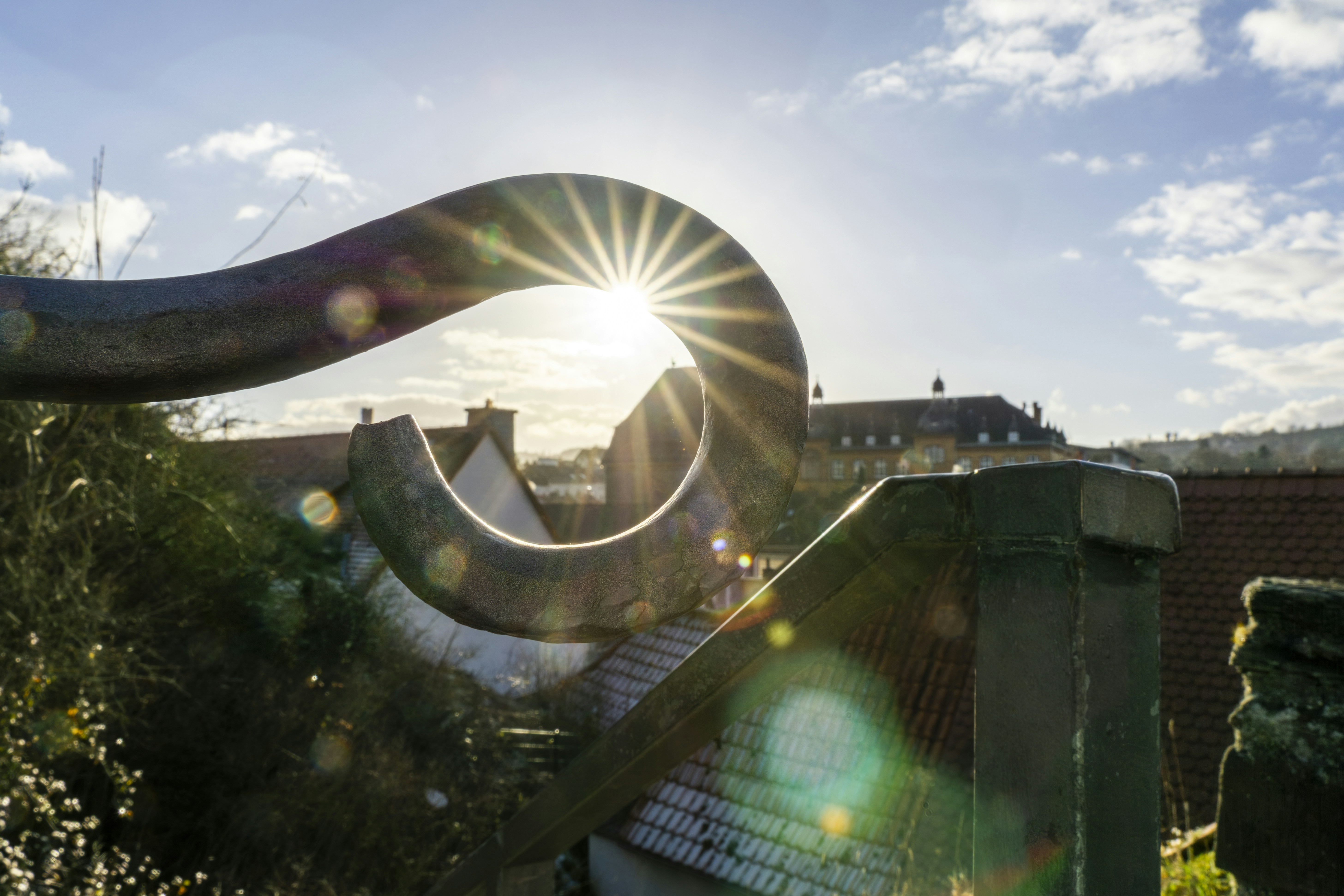 Sunburst Through a Curved Railing Over a Rooftop Scene