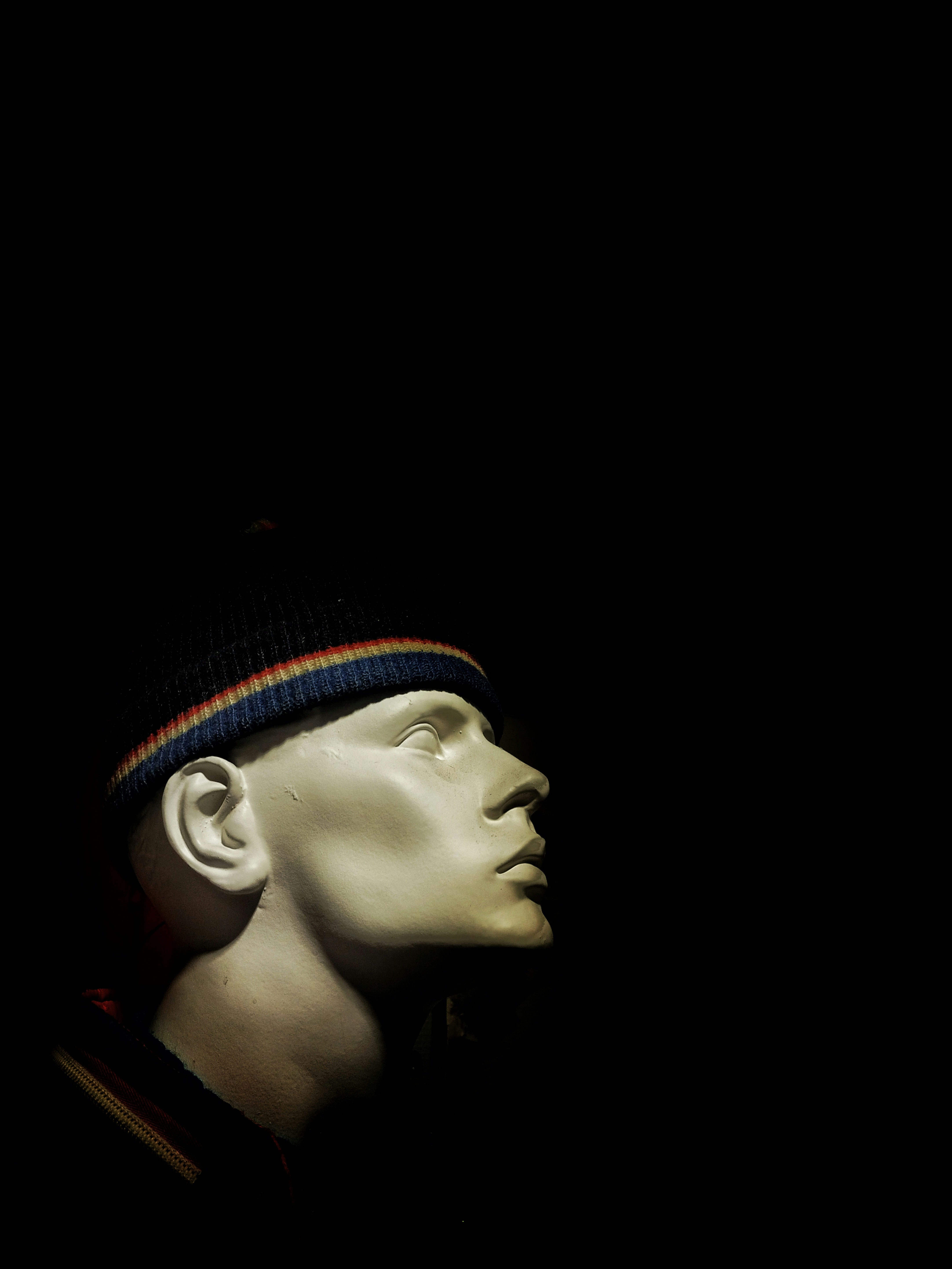 Mannequin head wearing a striped beanie hat.