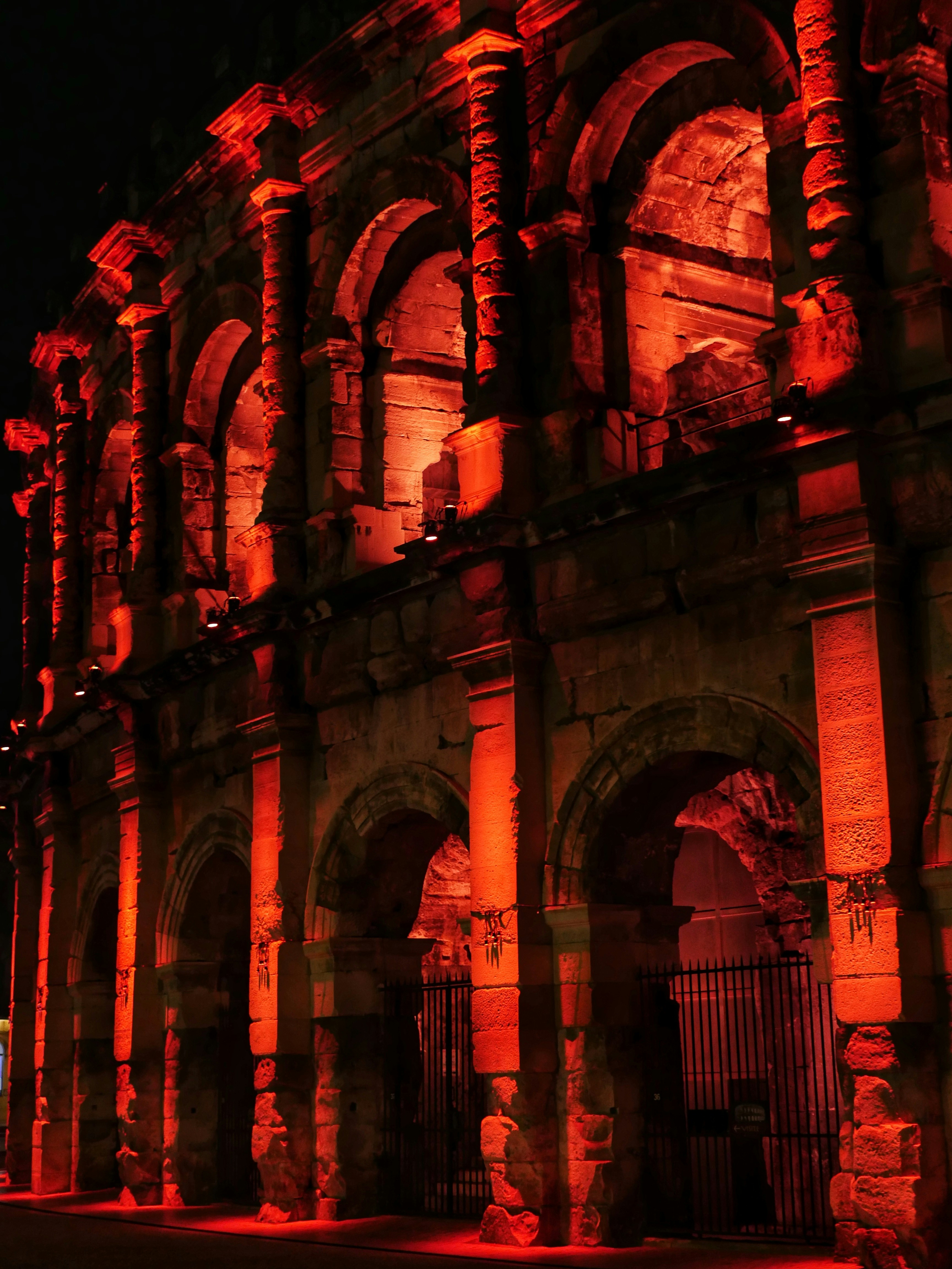 Red Echoes of an Ancient Arcade: Night Illumination on Stone Arches