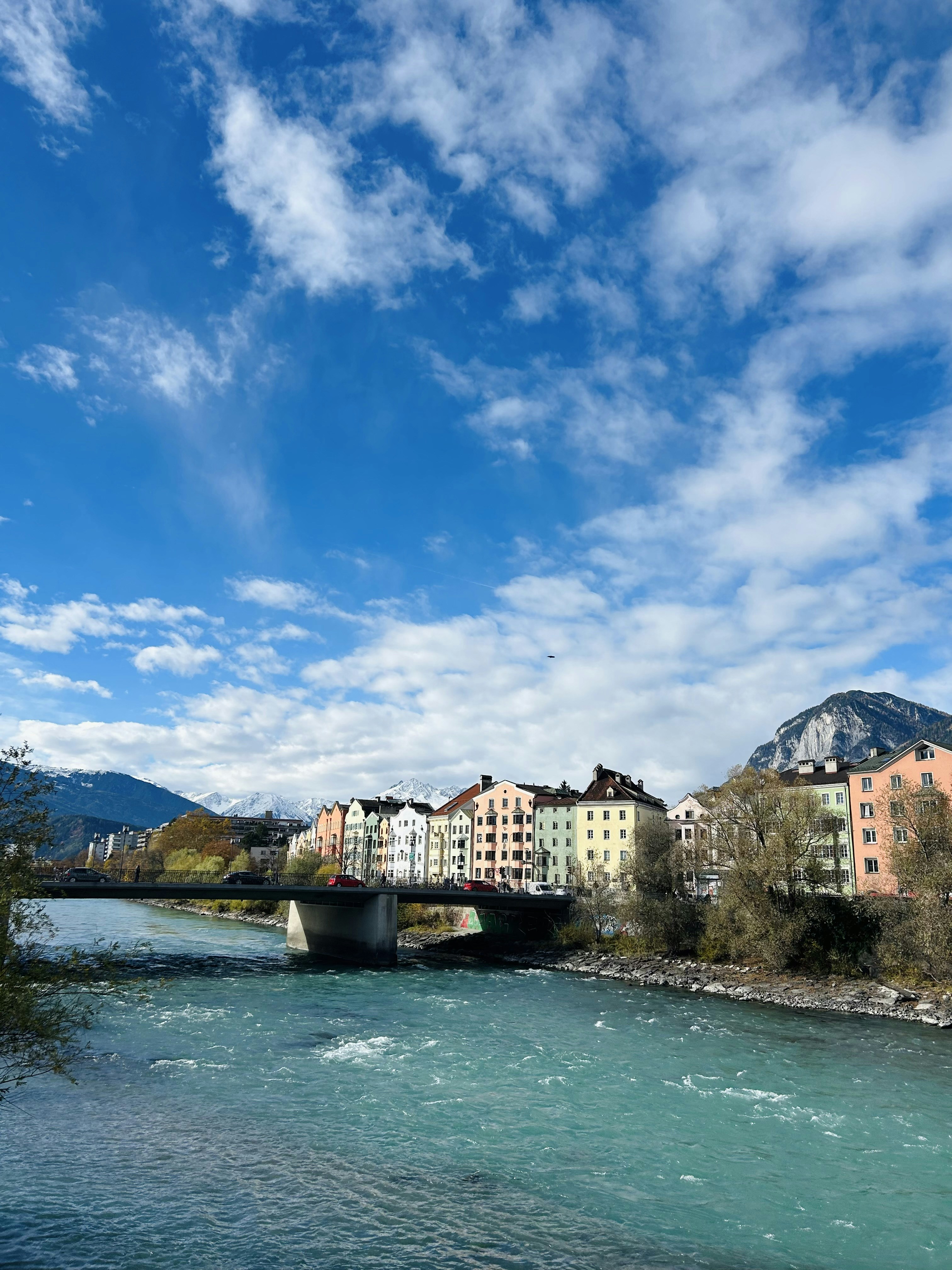 Colorful riverside houses meet a calm turquoise stream under a bright sky
