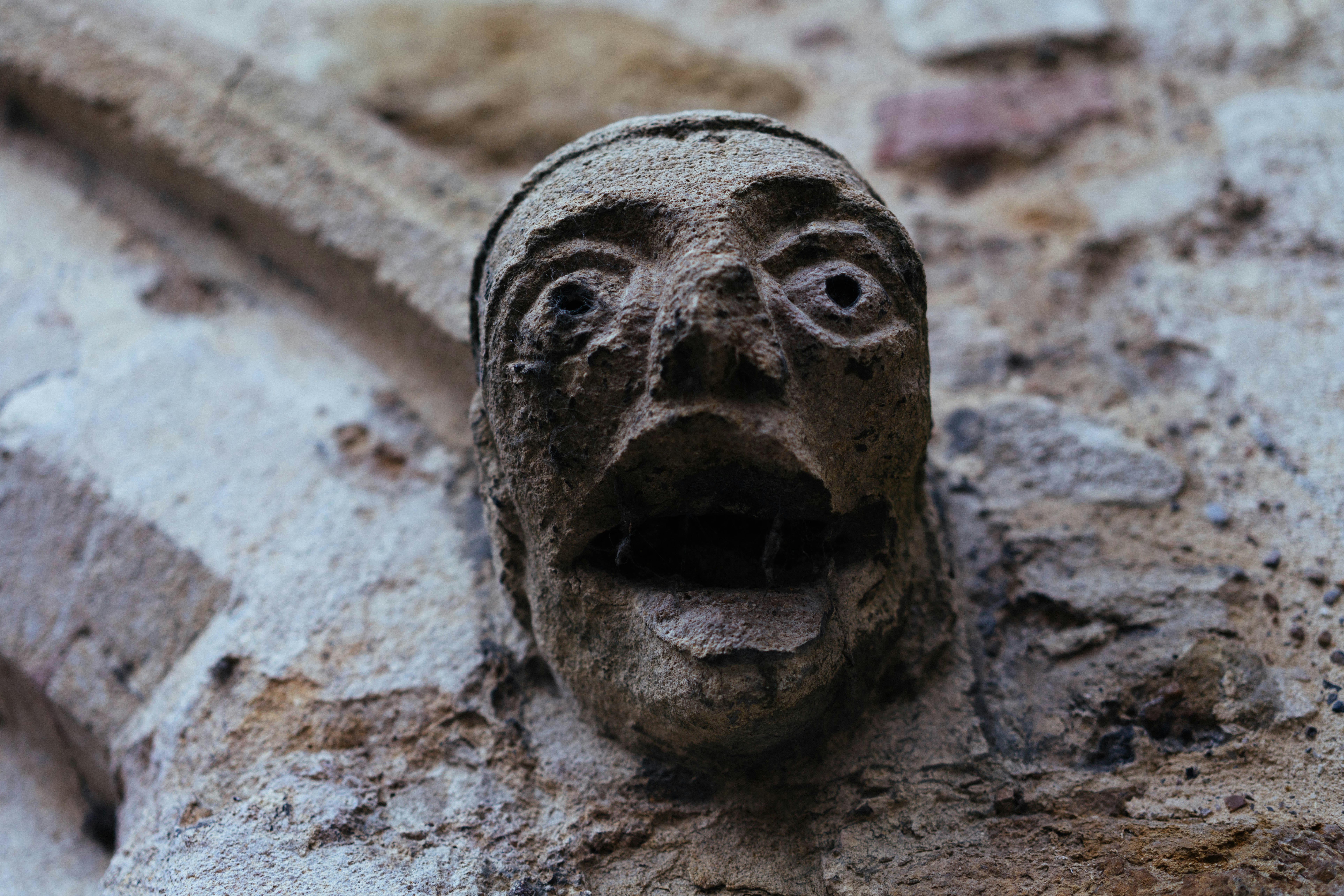 A stone carving of a screaming face on a building. photo – Free ...