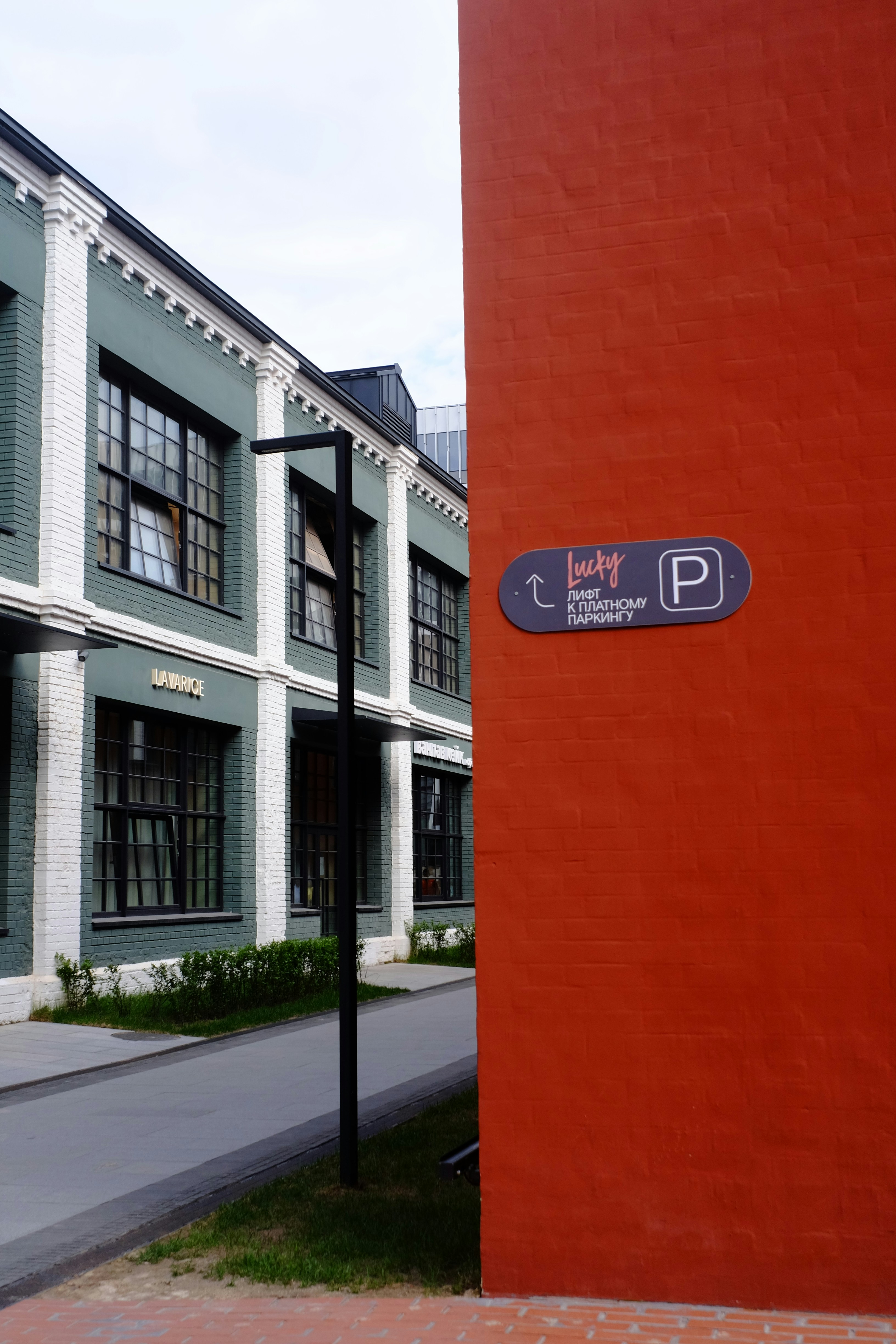 Green building with red wall and parking sign