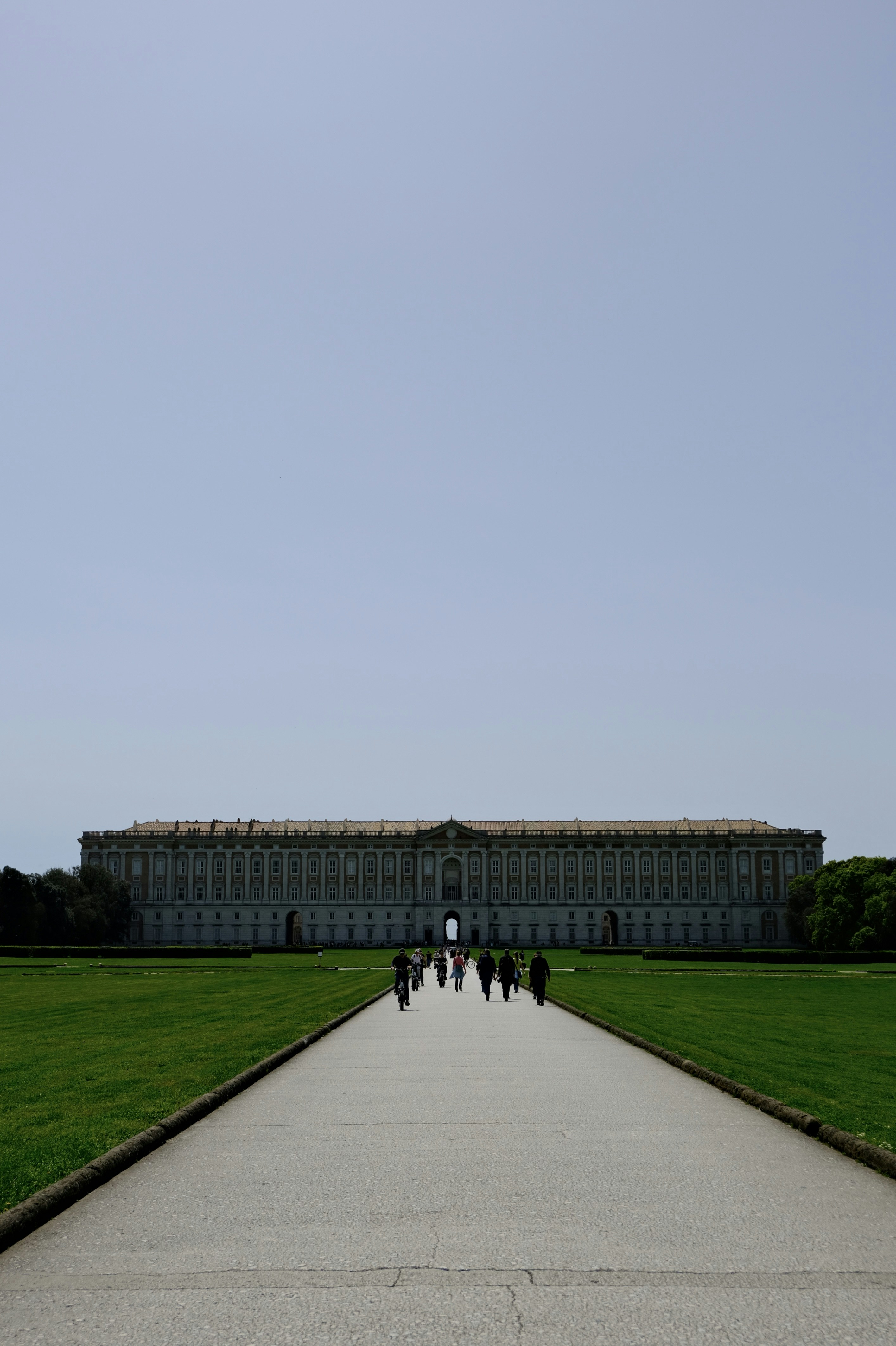 Grand palace with a long pathway and green lawn.