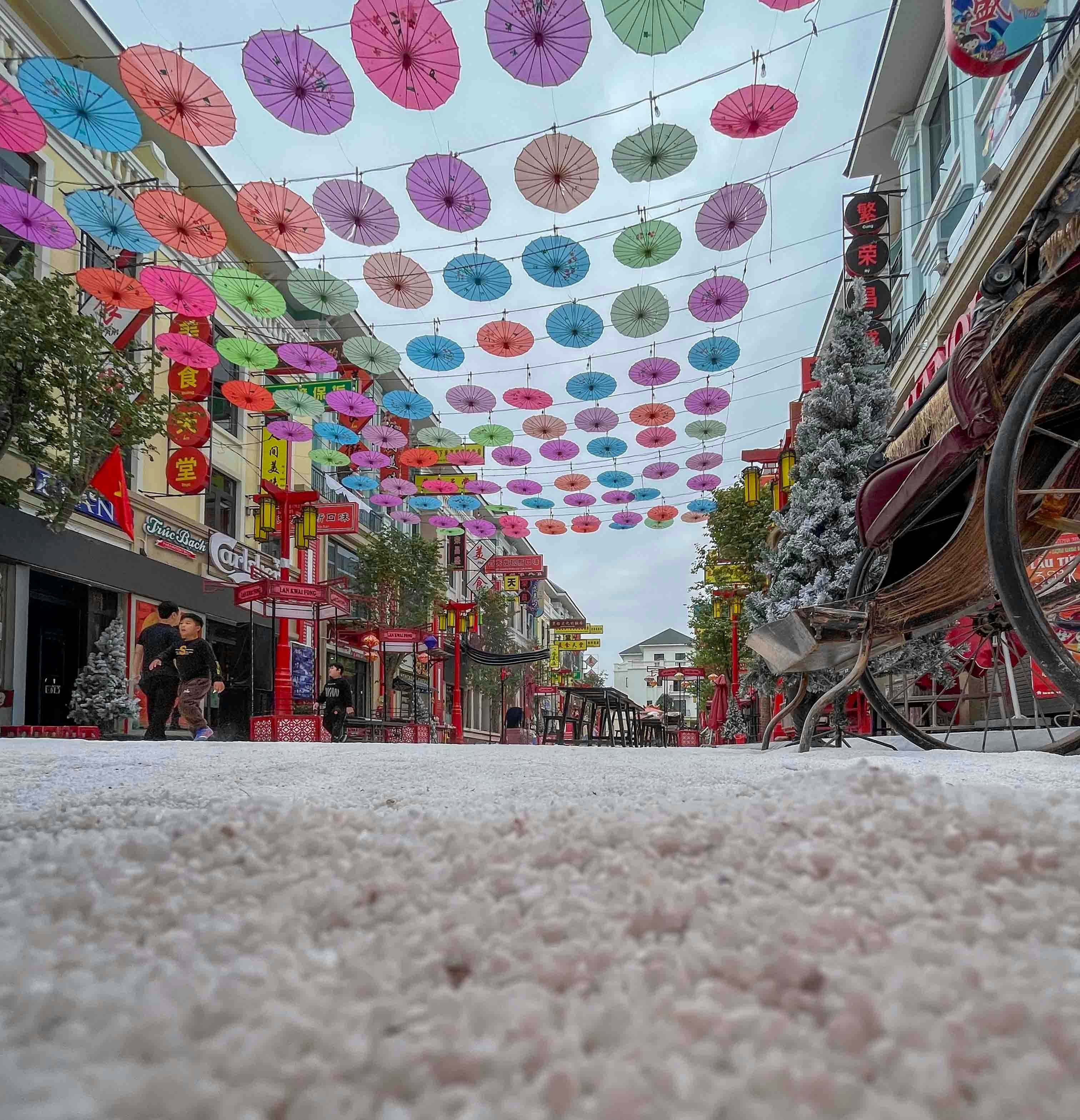 Candy-colored parade: a pedestrian street beneath lantern tattoos of sky