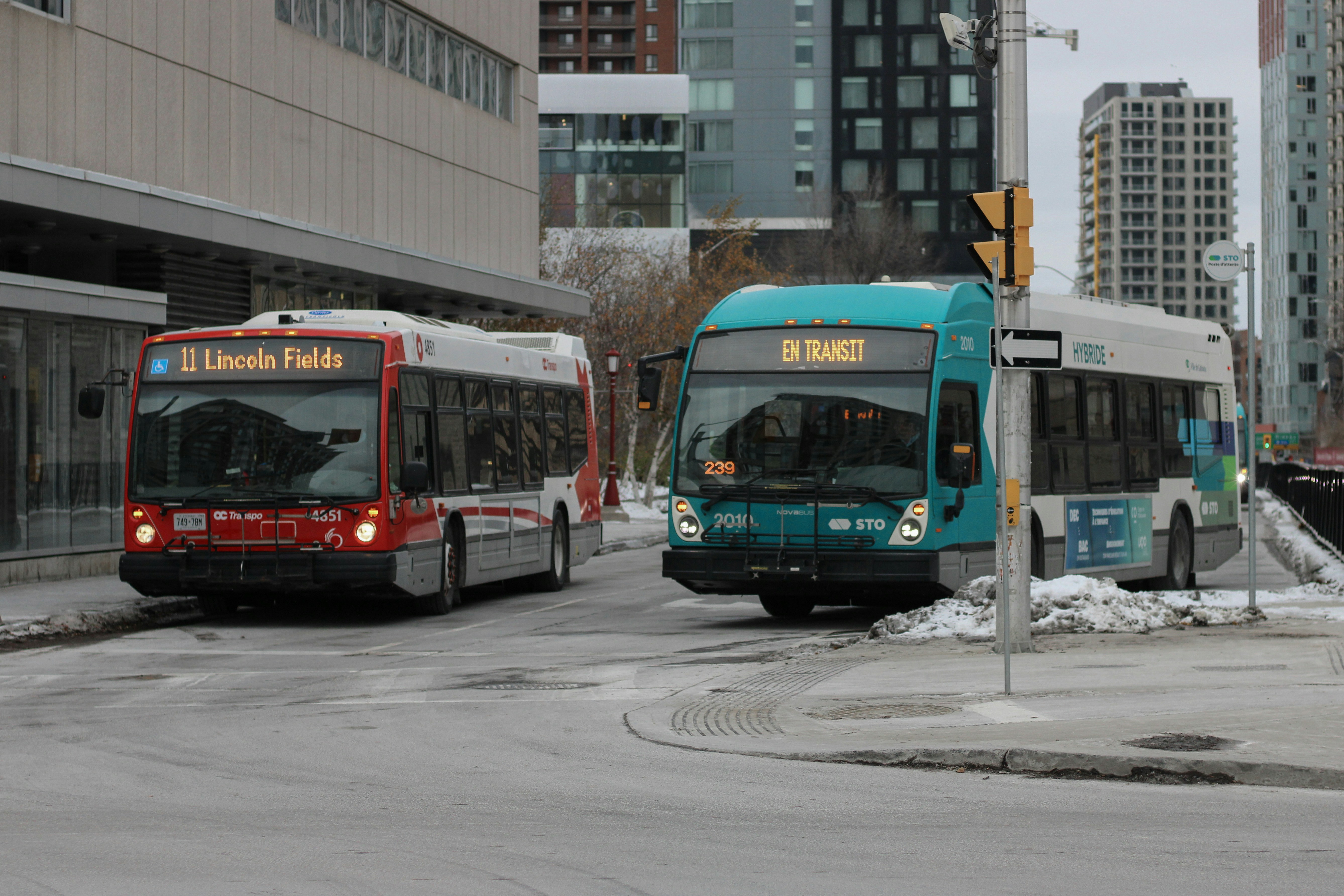 A pair of city buses meet at a snowy street corner