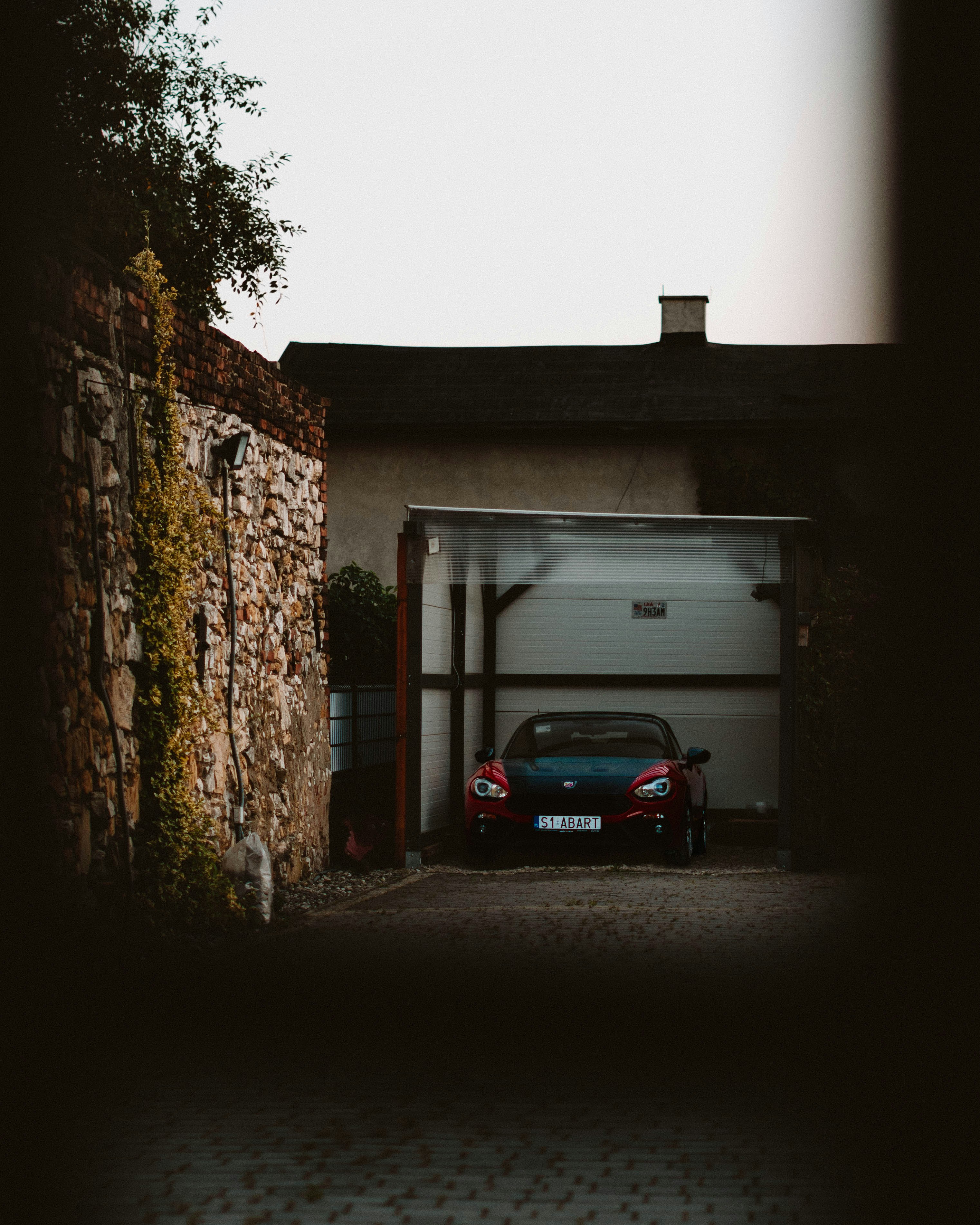 Red Roadster Emerges from Shadowed Garage