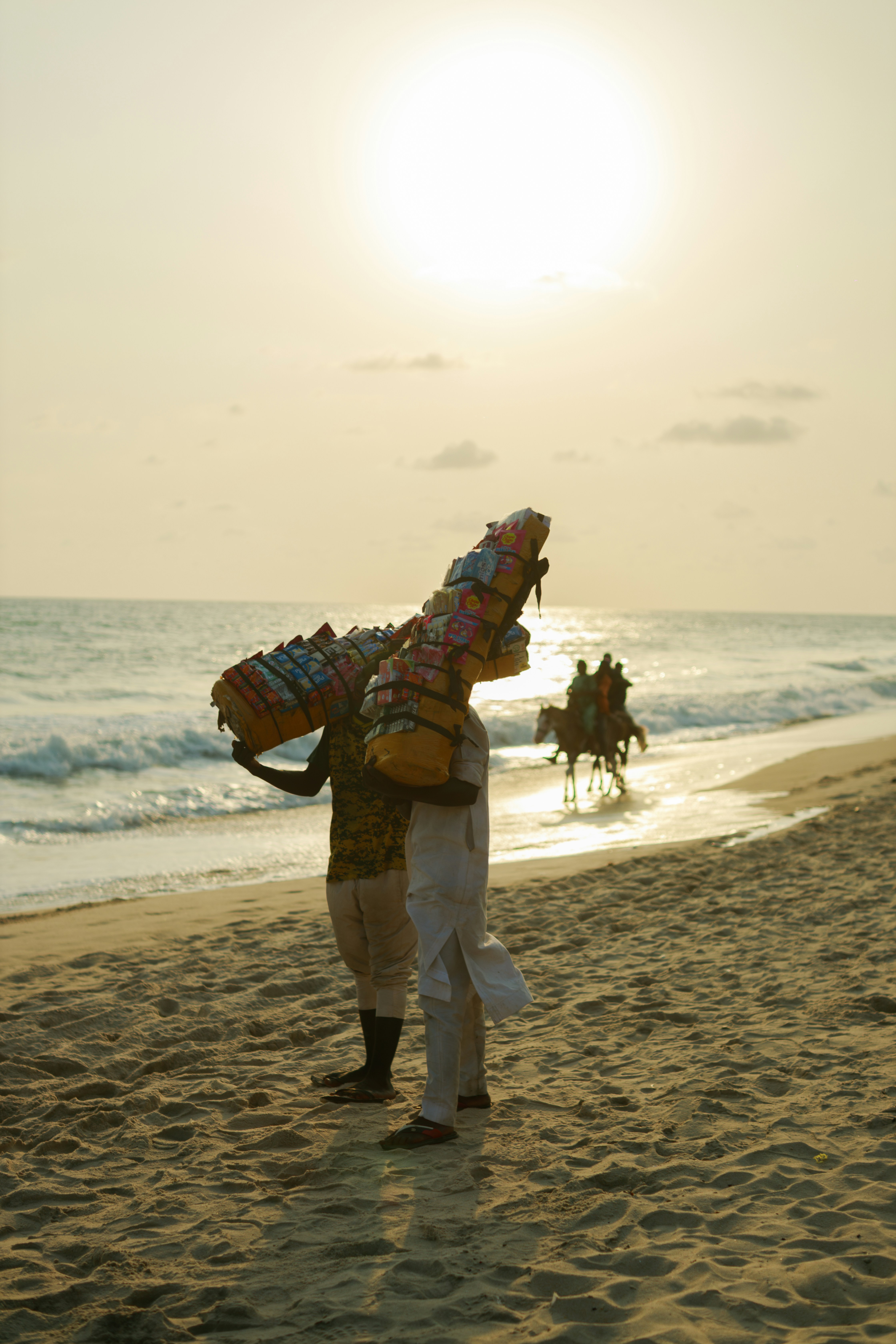 Carrying the Tide: Vendors on a Sunset Shore