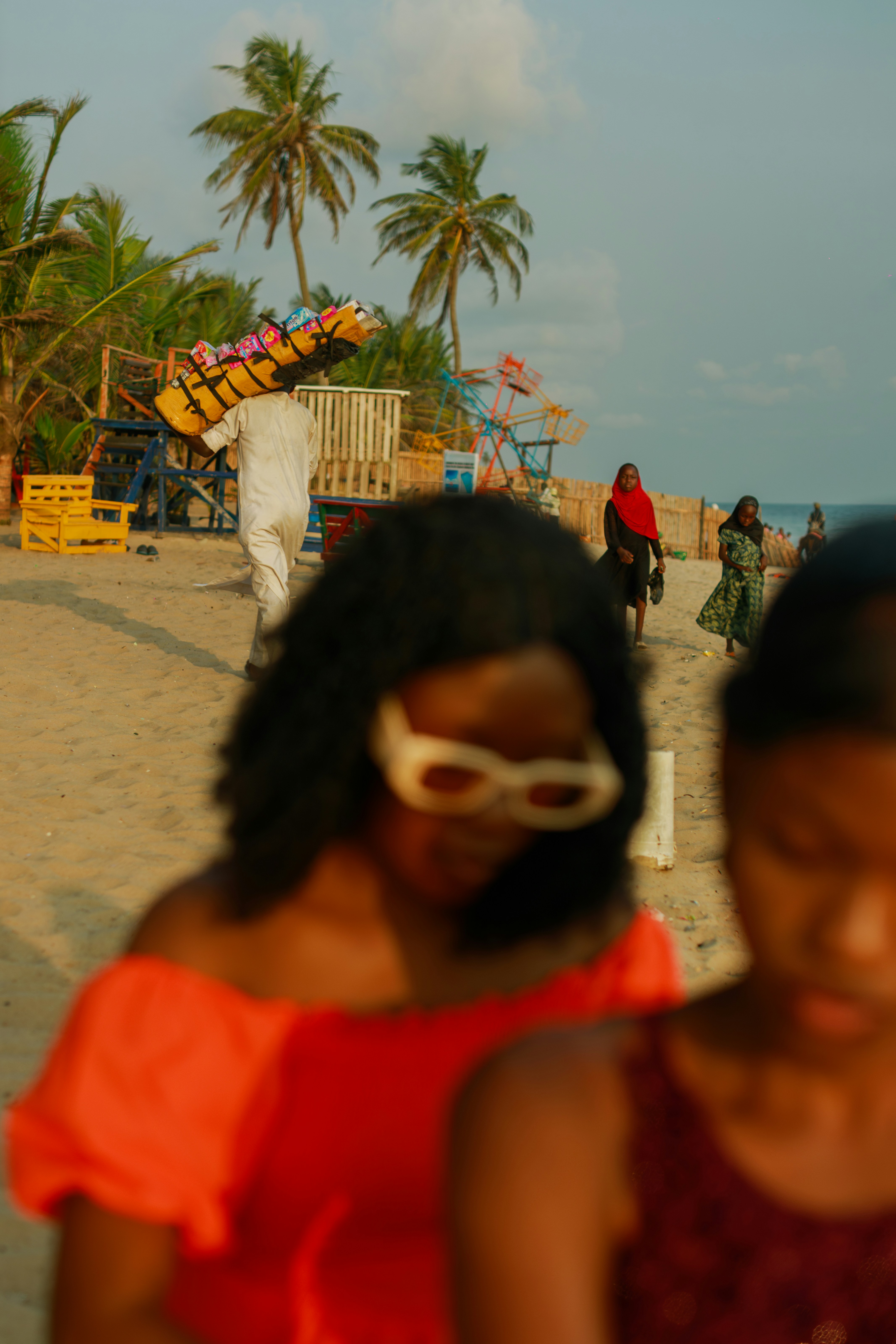 Sunlit Shore: Carrying Colorful Buoys Past Coastal Palm Shadows