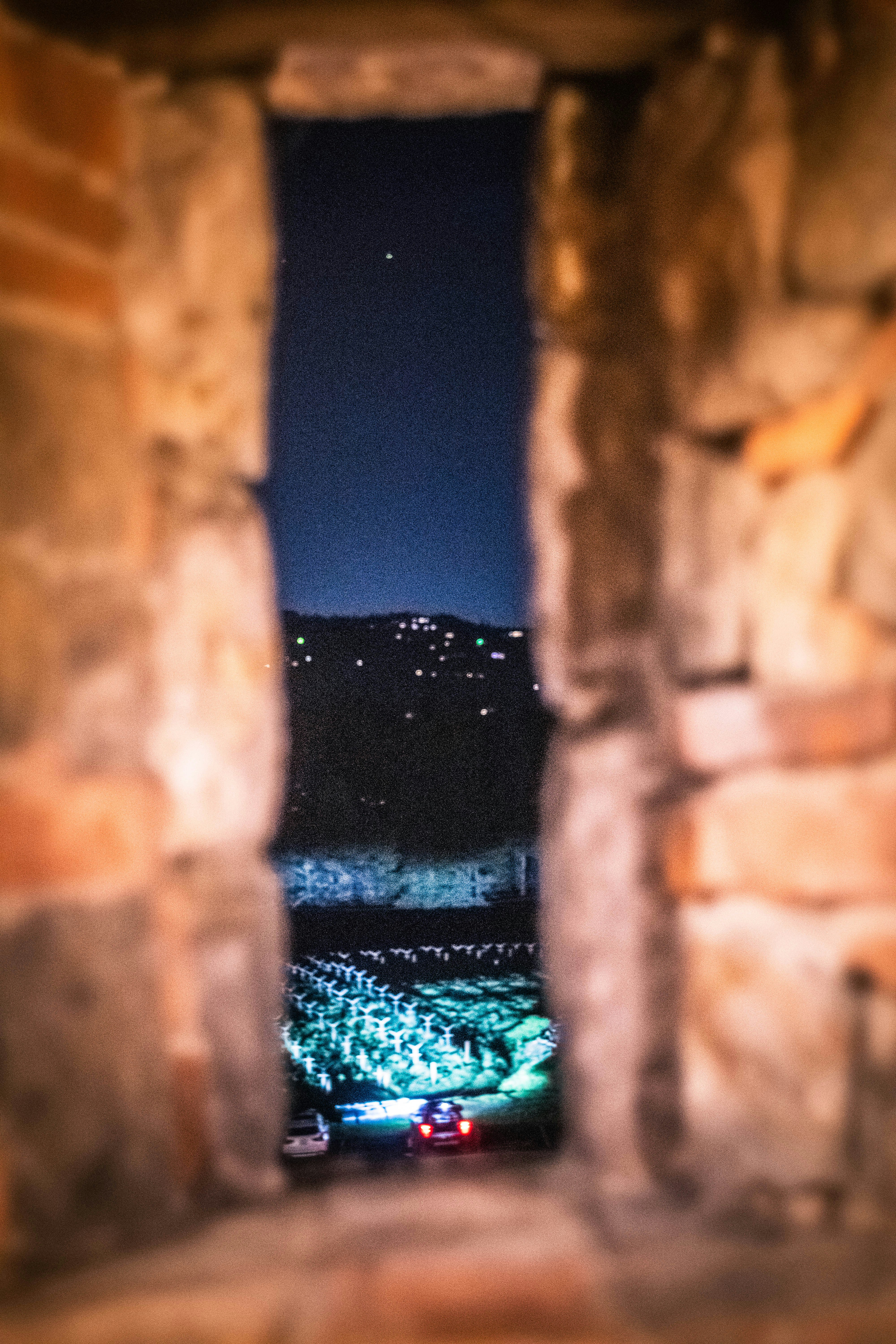 Moonlit Gaps: Night through an Ancient Arch toward the Distant Lights