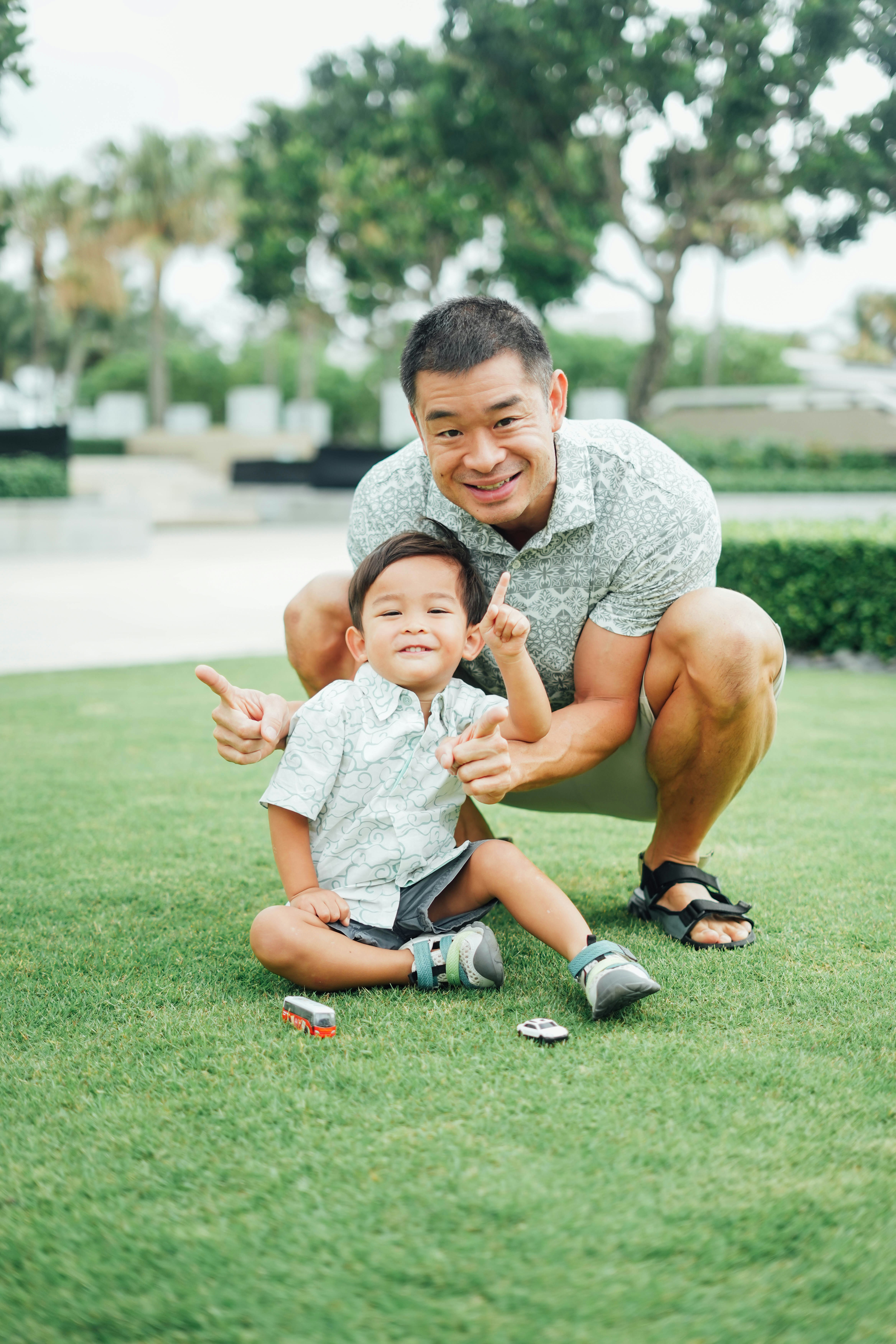 Father's joyful crouch: a toddler's triumphant grin on the lawn