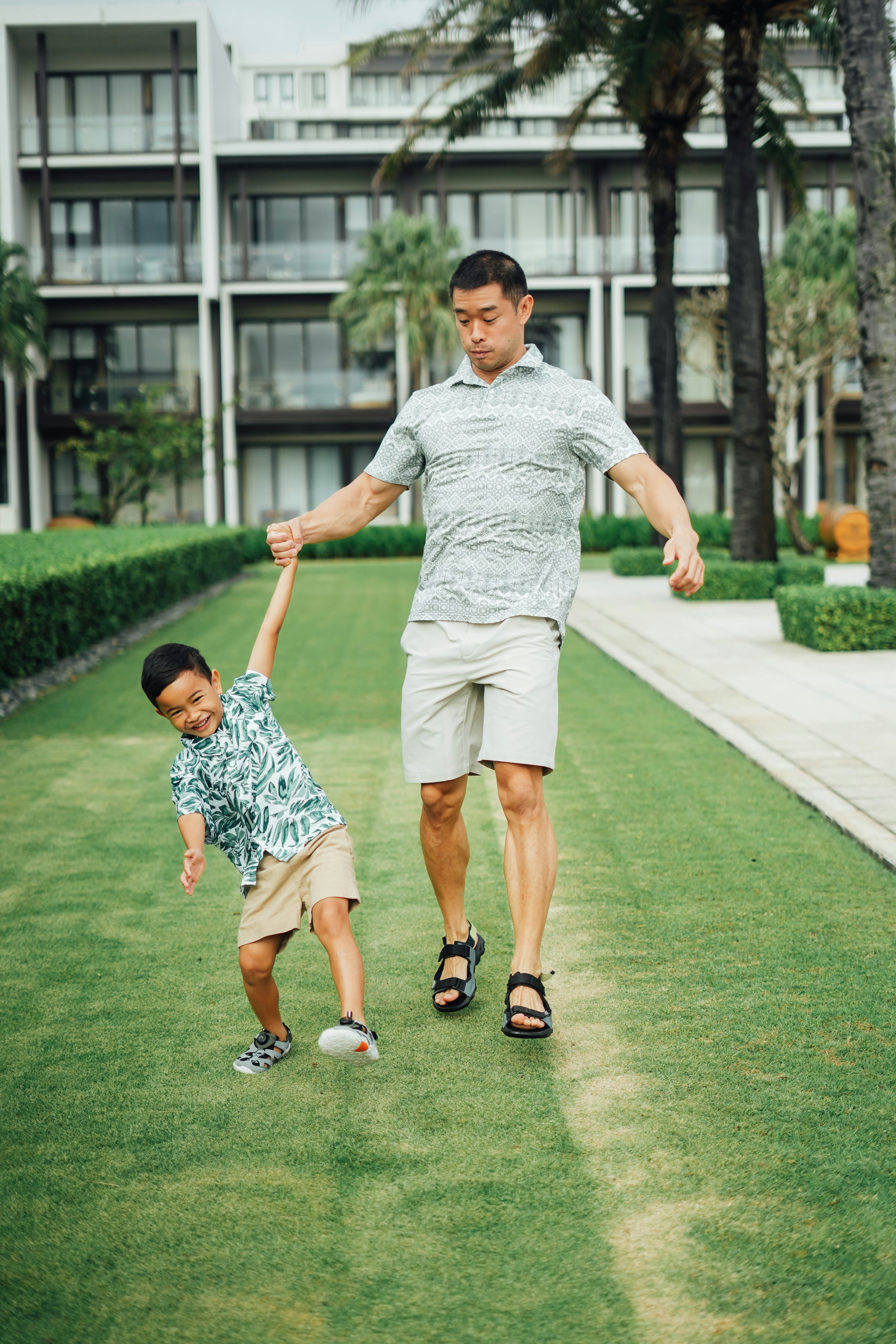 Father and Son Swing Across a Green Corridor