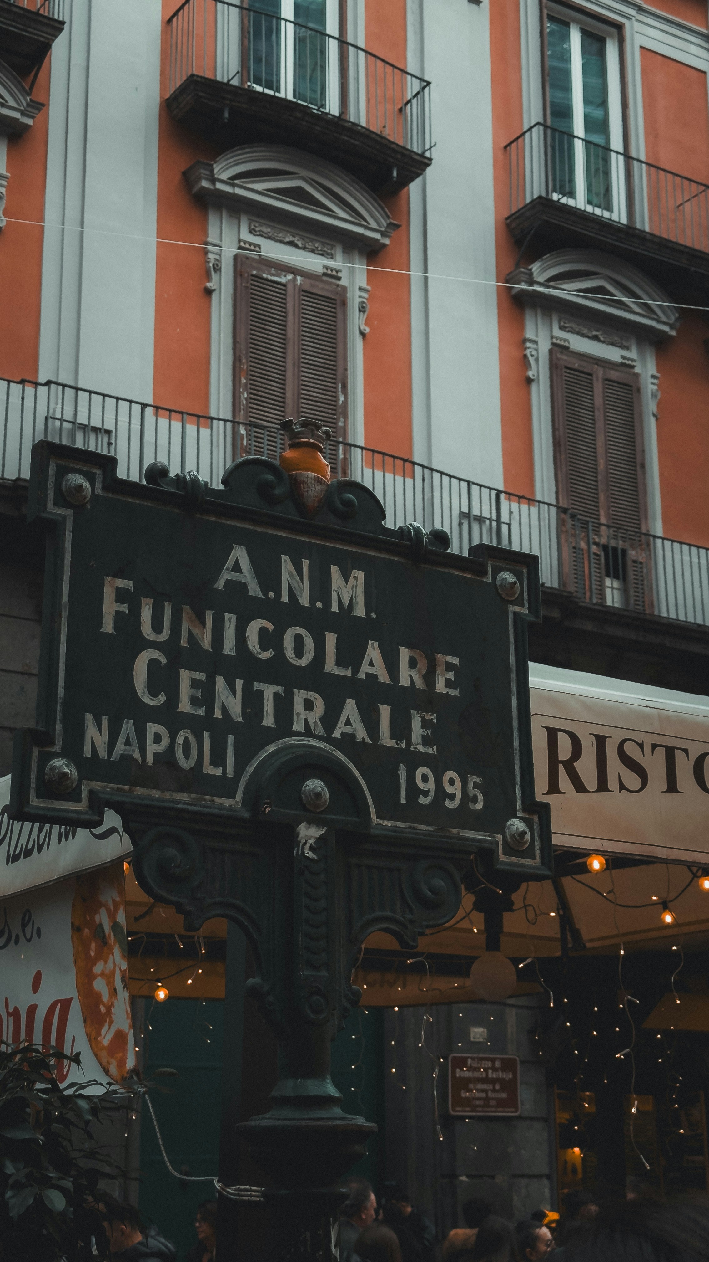 Historic signpost with café facade under warm evening lights