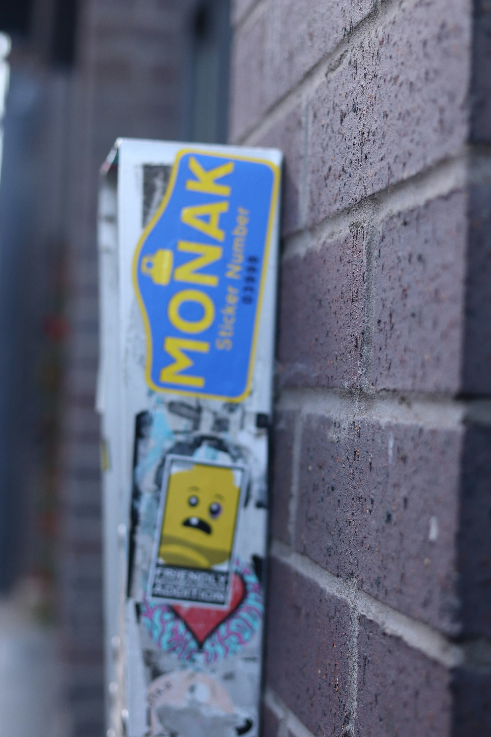 Stickered Mailbox Adrift on a Bricked Wall