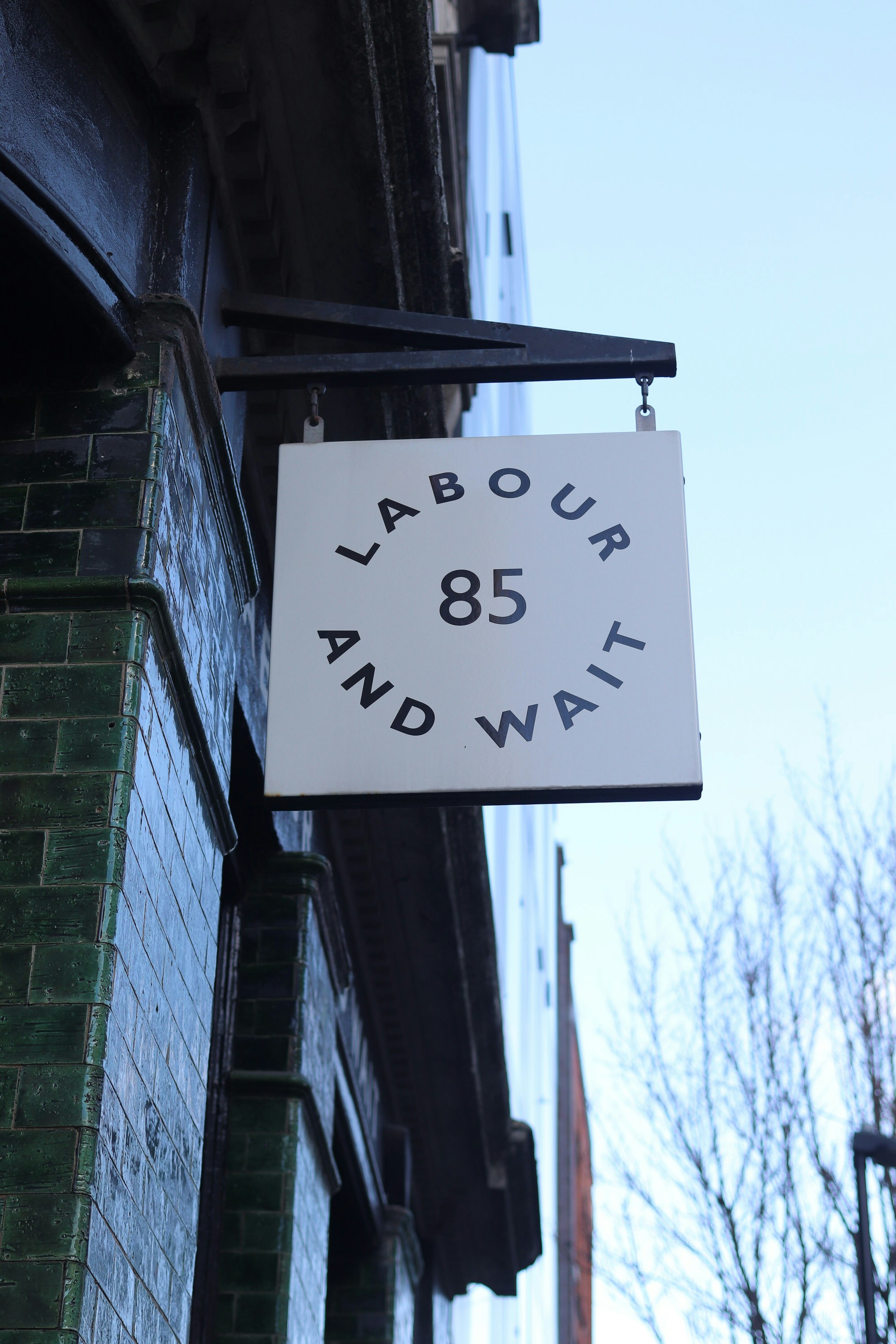 Signboard at Dusk: Labour and Wait Over a Green Tile Wall