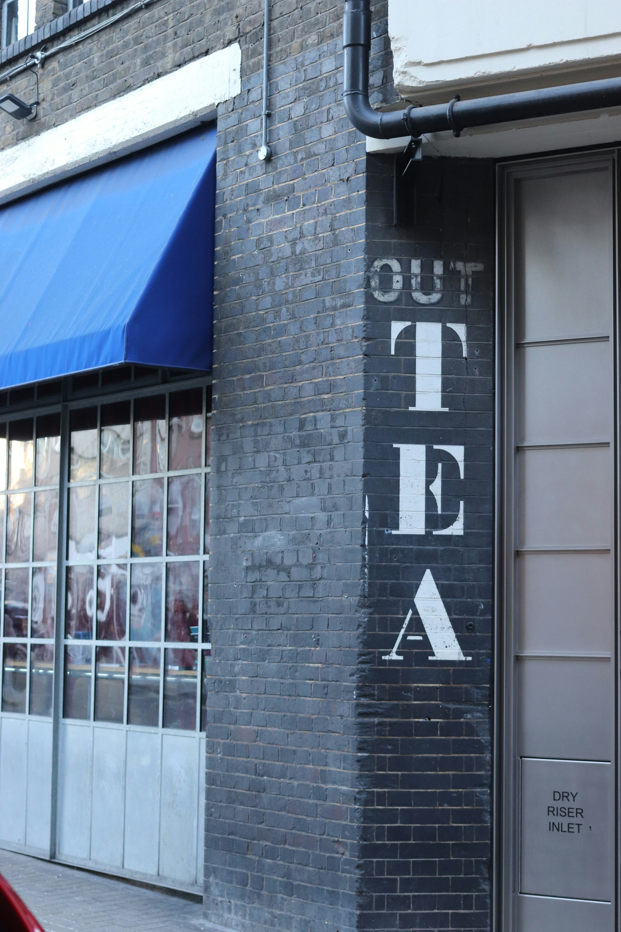 Urban storefront: blue awning and bold vertical sign on a brick wall