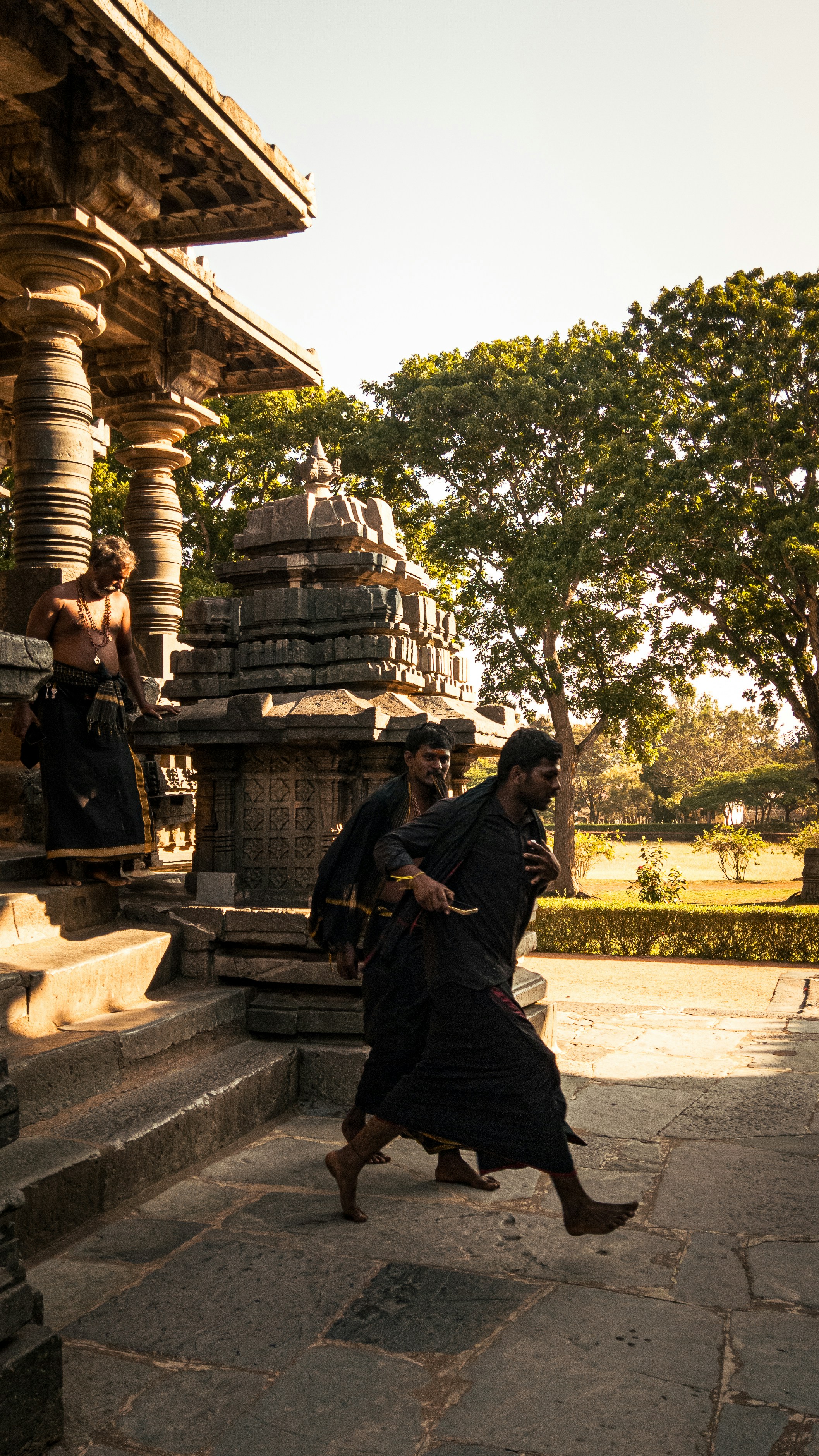 Men in traditional attire walk near ancient stone temple structures ...