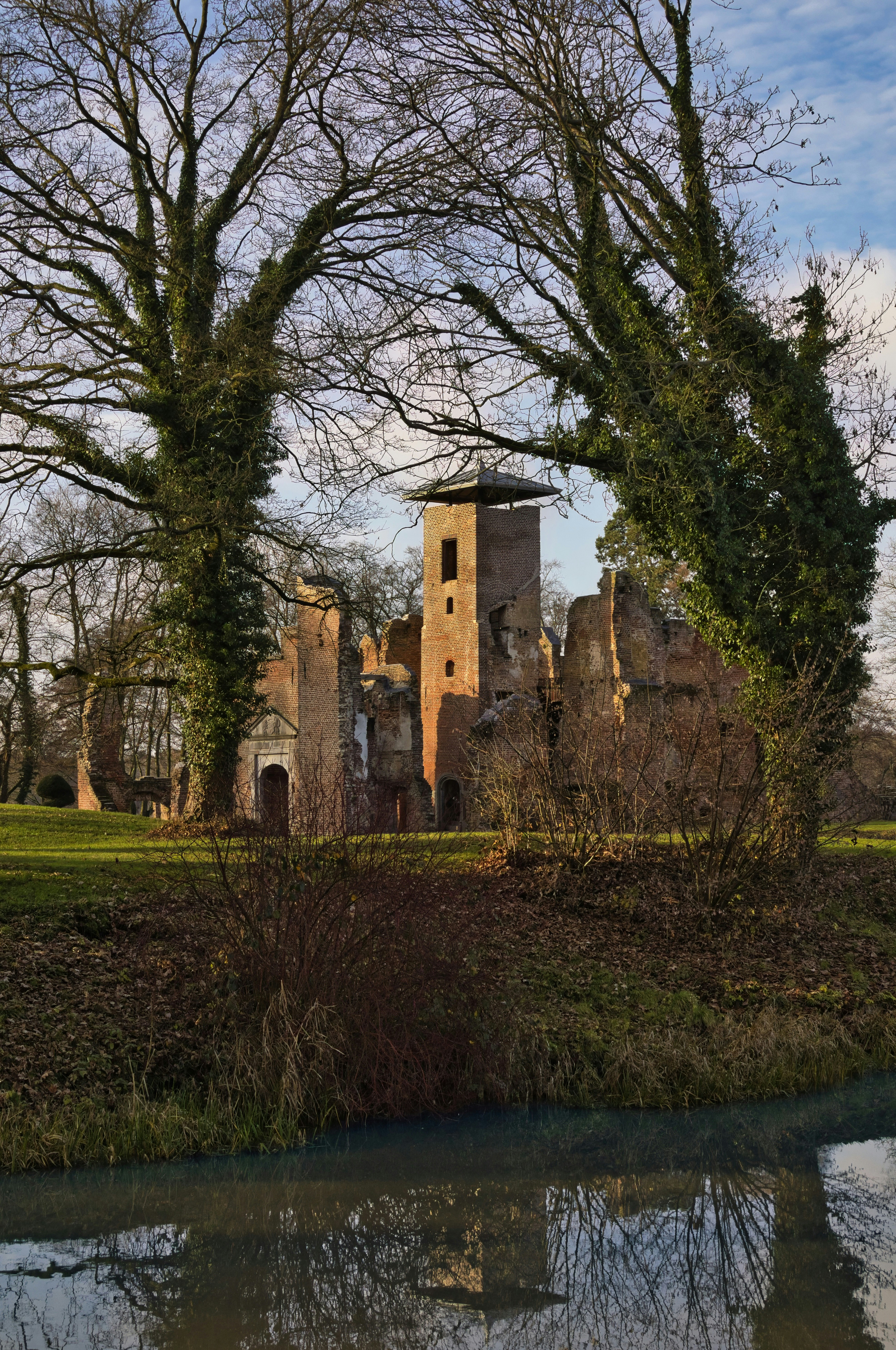 Ruin of Ivy-Wrapped Tower Amid Trees by a Reflective Stream