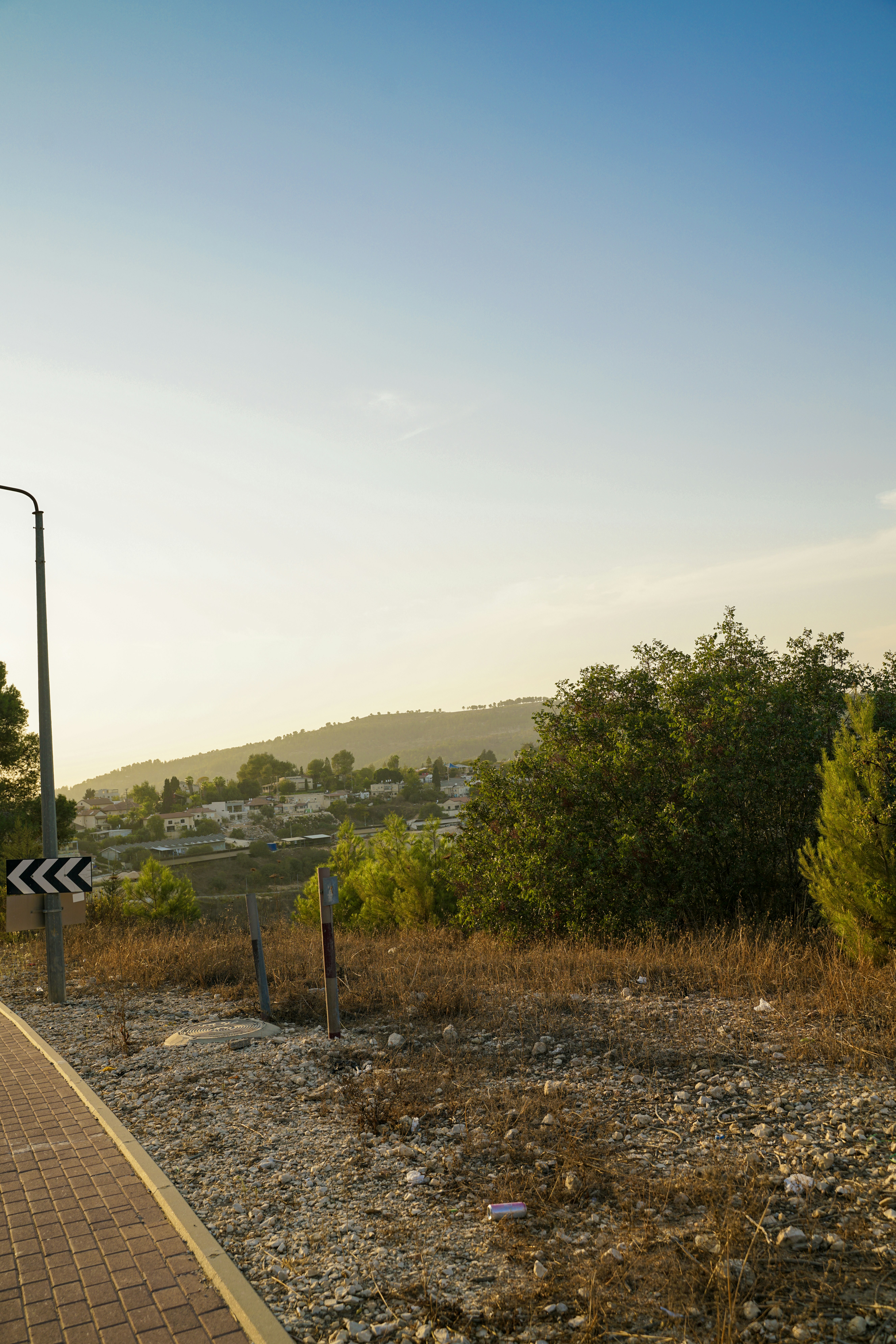 Sunlit hillside road into a quiet town