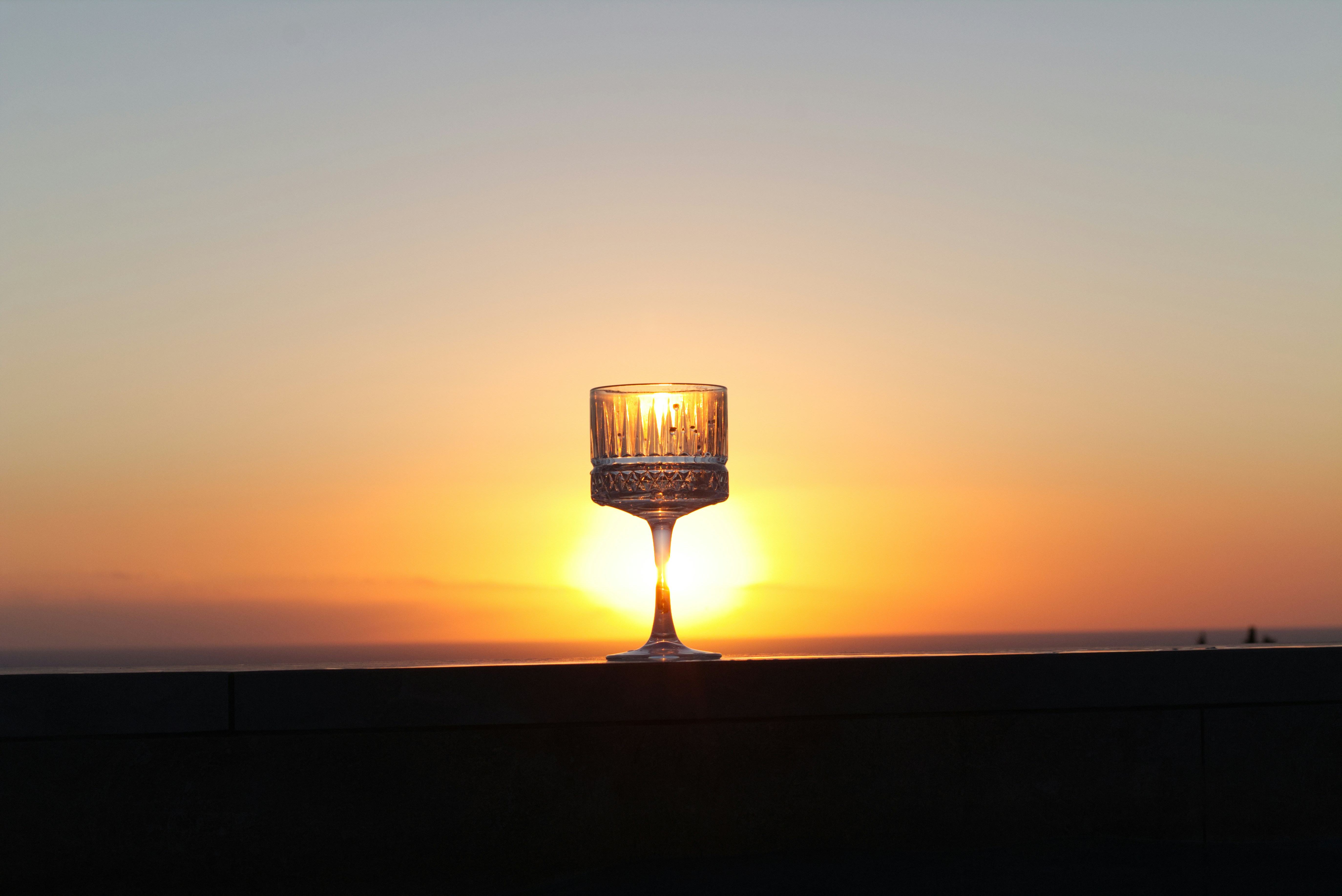 Sunlit Glass: a solitary goblet against a coastal horizon