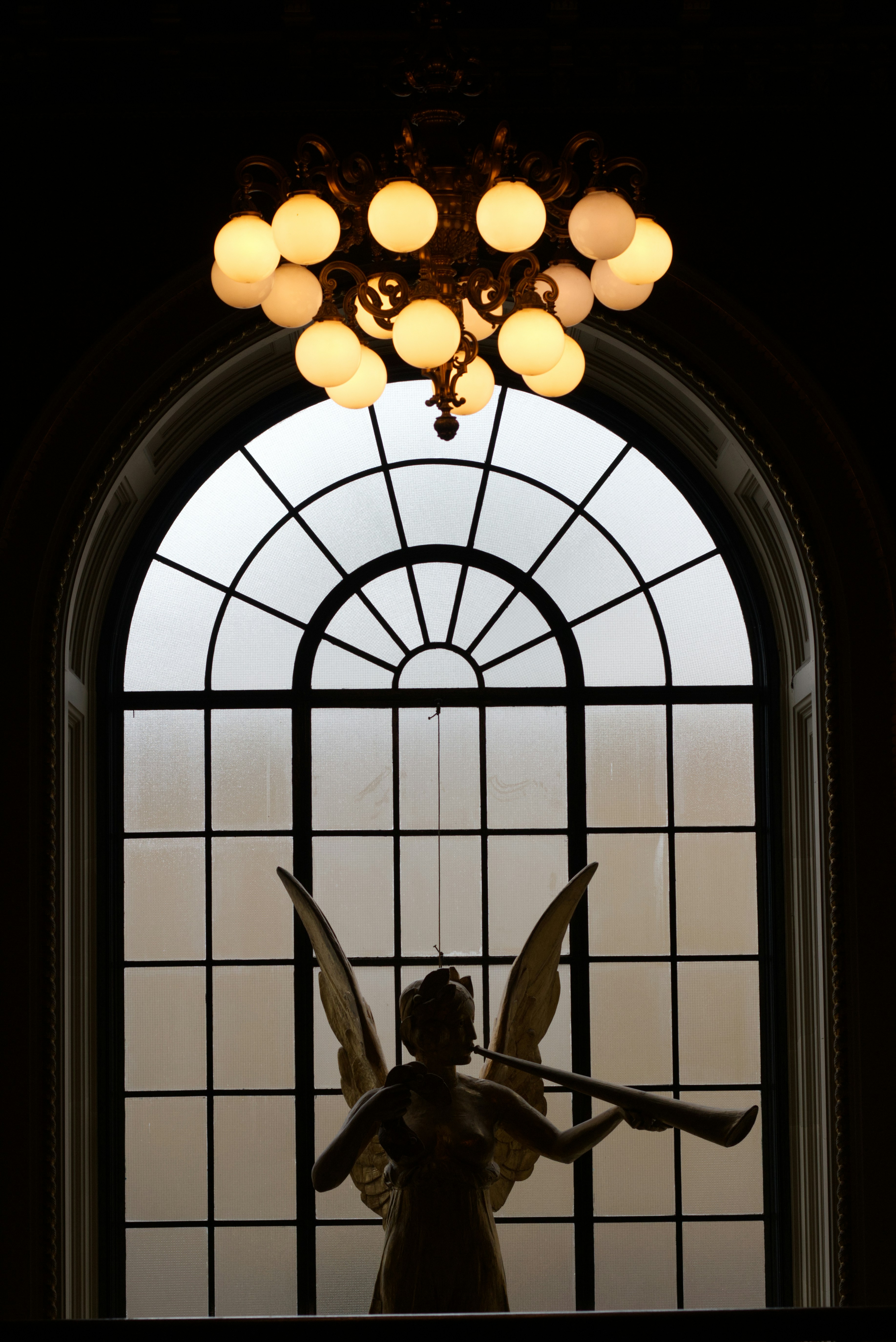 Silhouette of a Winged Figure in Front of a Grand Arched Window