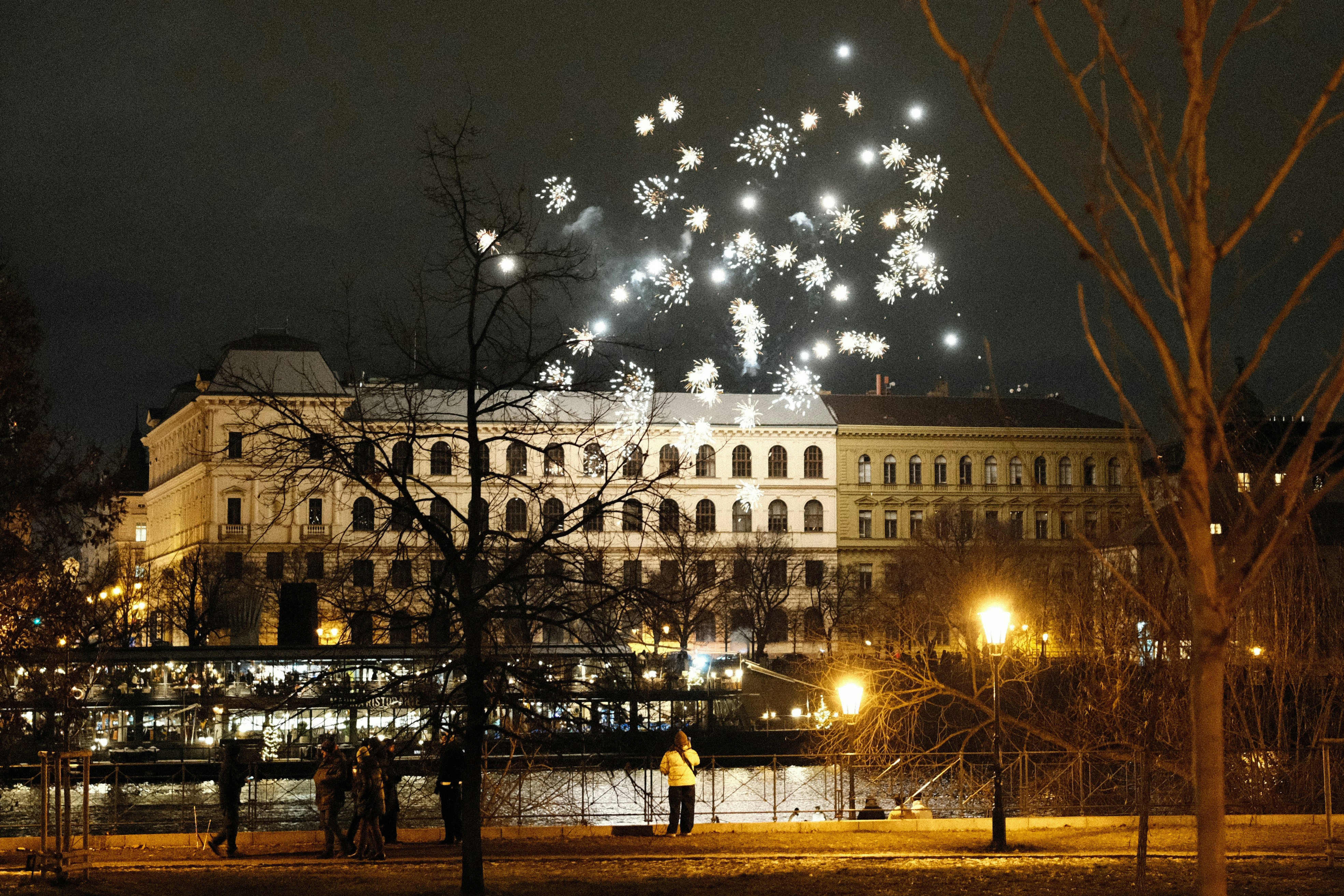 Fireworks over the riverside cityscape: nighttime glow on a historic facade