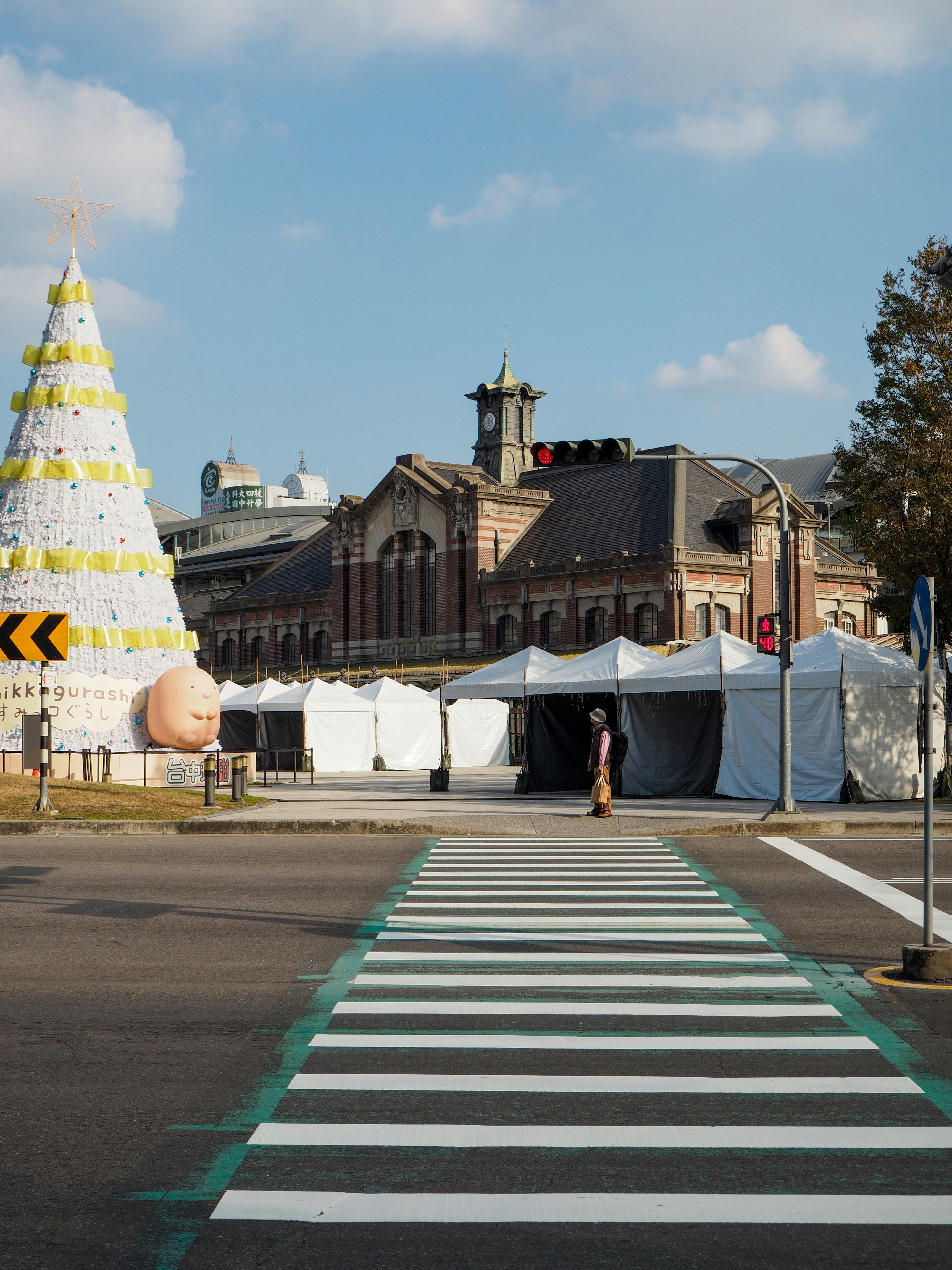 Tented market row fronts a historic brick building beside a festive cone sculpture