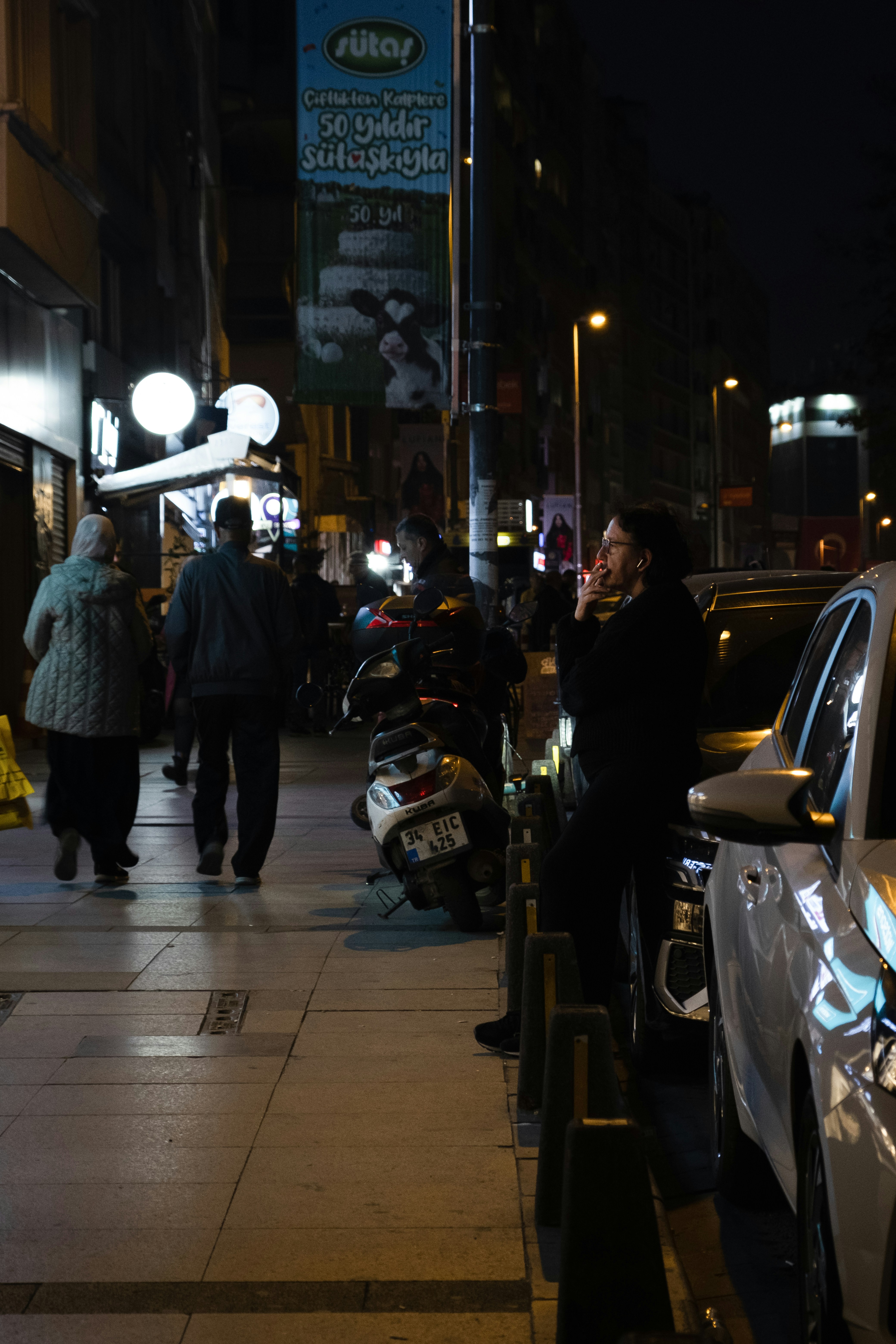 Night Street Portrait: A Contemplative Moment by the Curb
